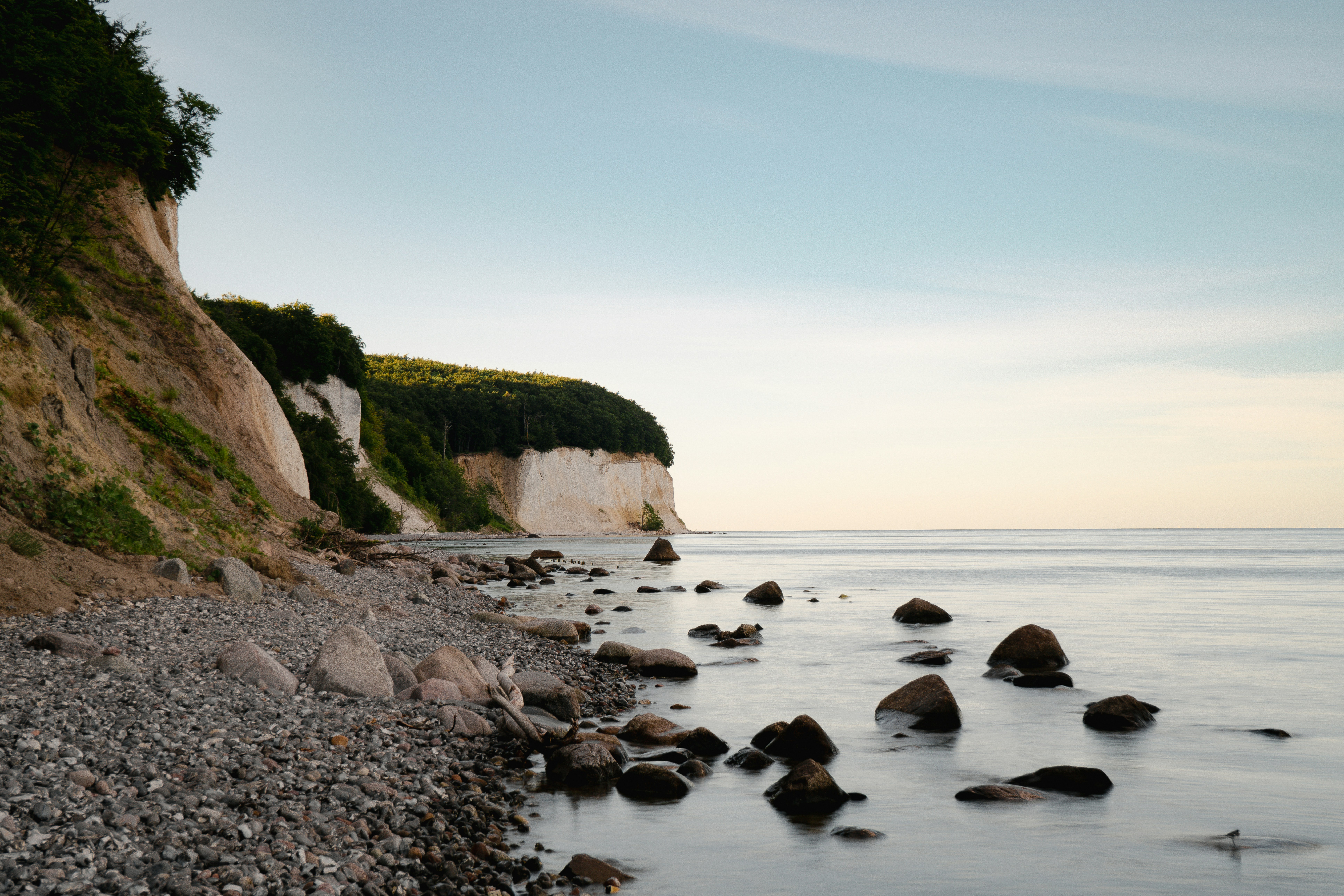 Cliffside shore at dusk: pebbled beach meeting calm sea