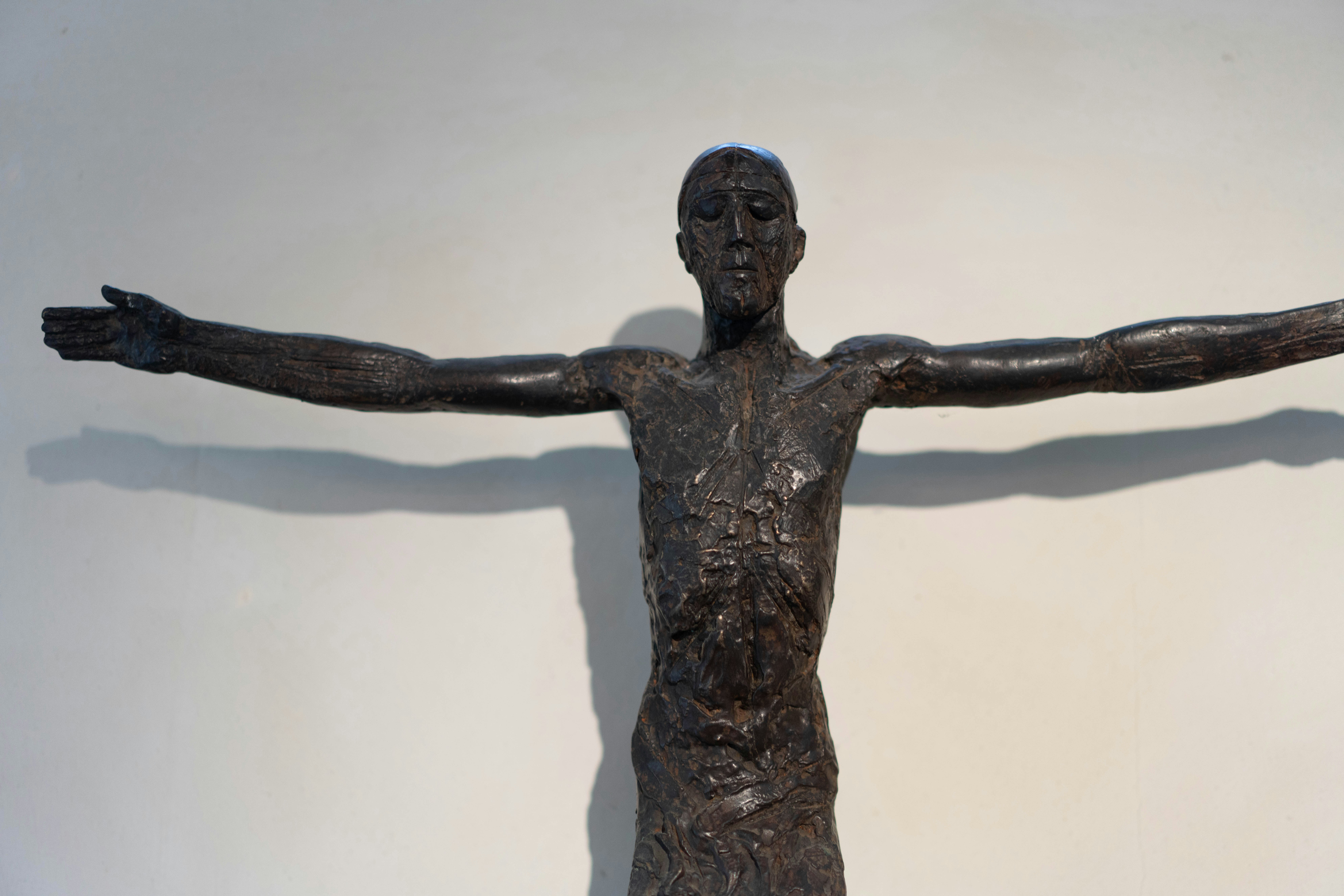 Outstretched Silence: A Bronze Figure Against Light
