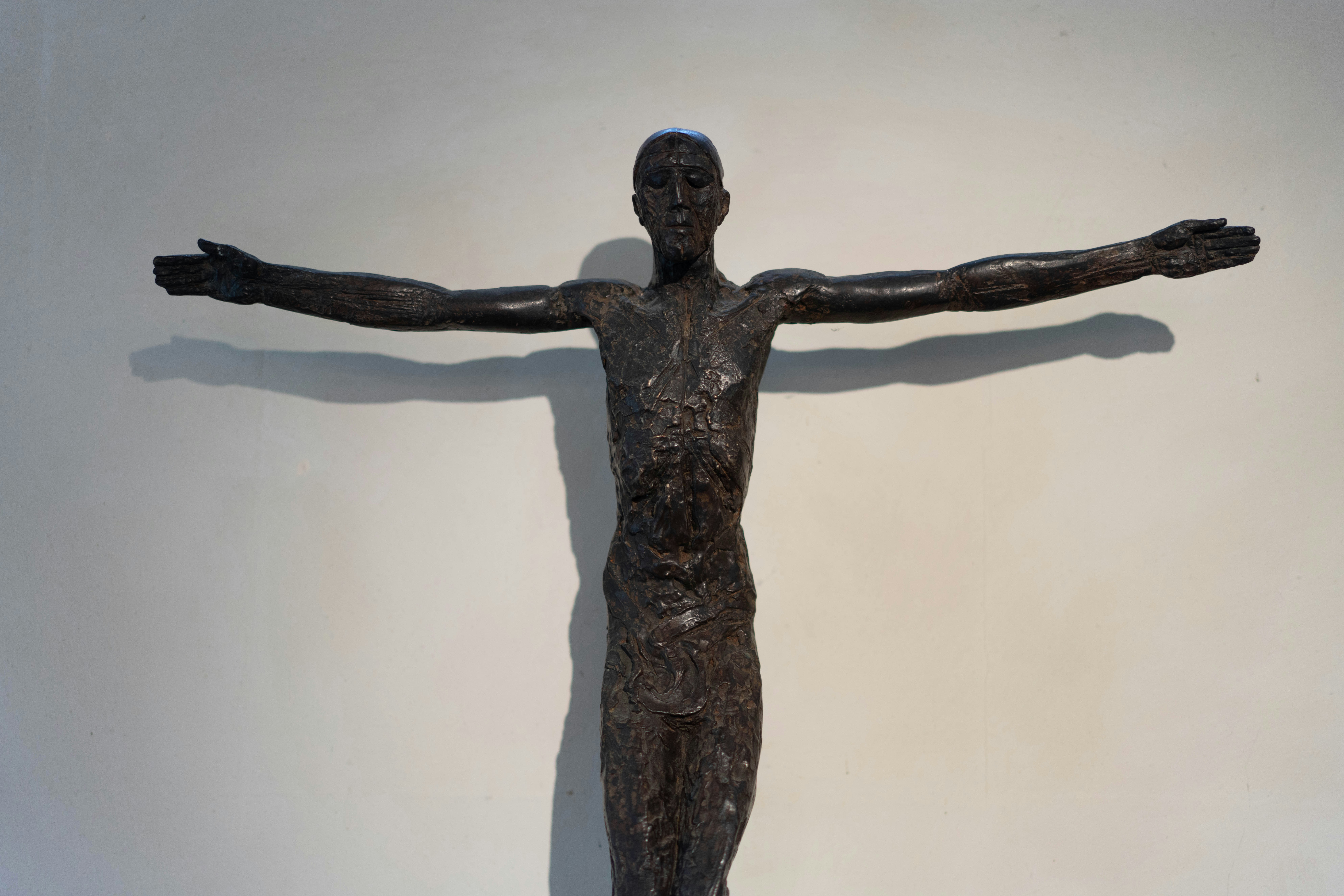 Arms Open: A Sculpted Figure Against a Soft Shadowed Wall