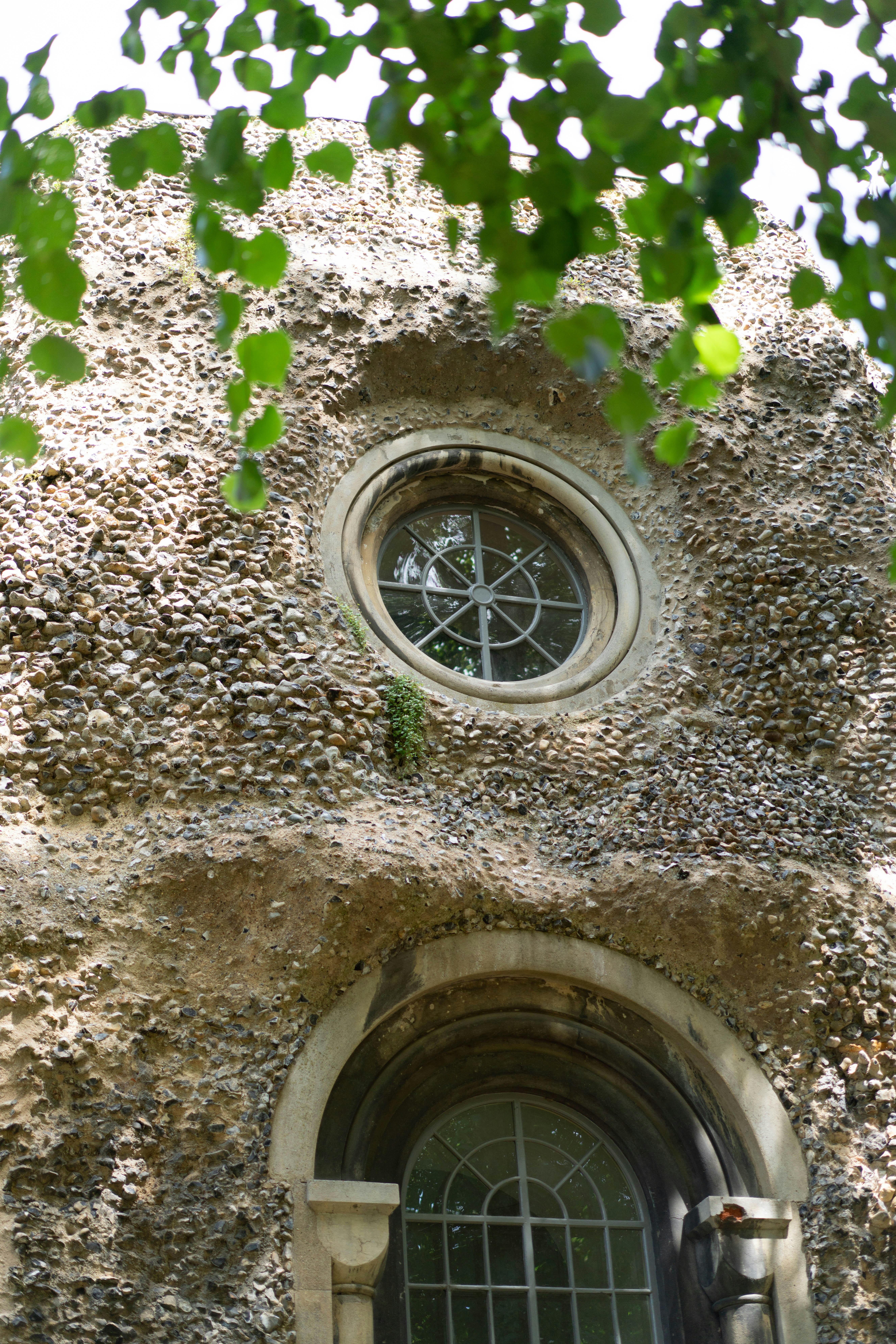 Circular Windows in Pebble Wall: Nature Framing of an Old Facade