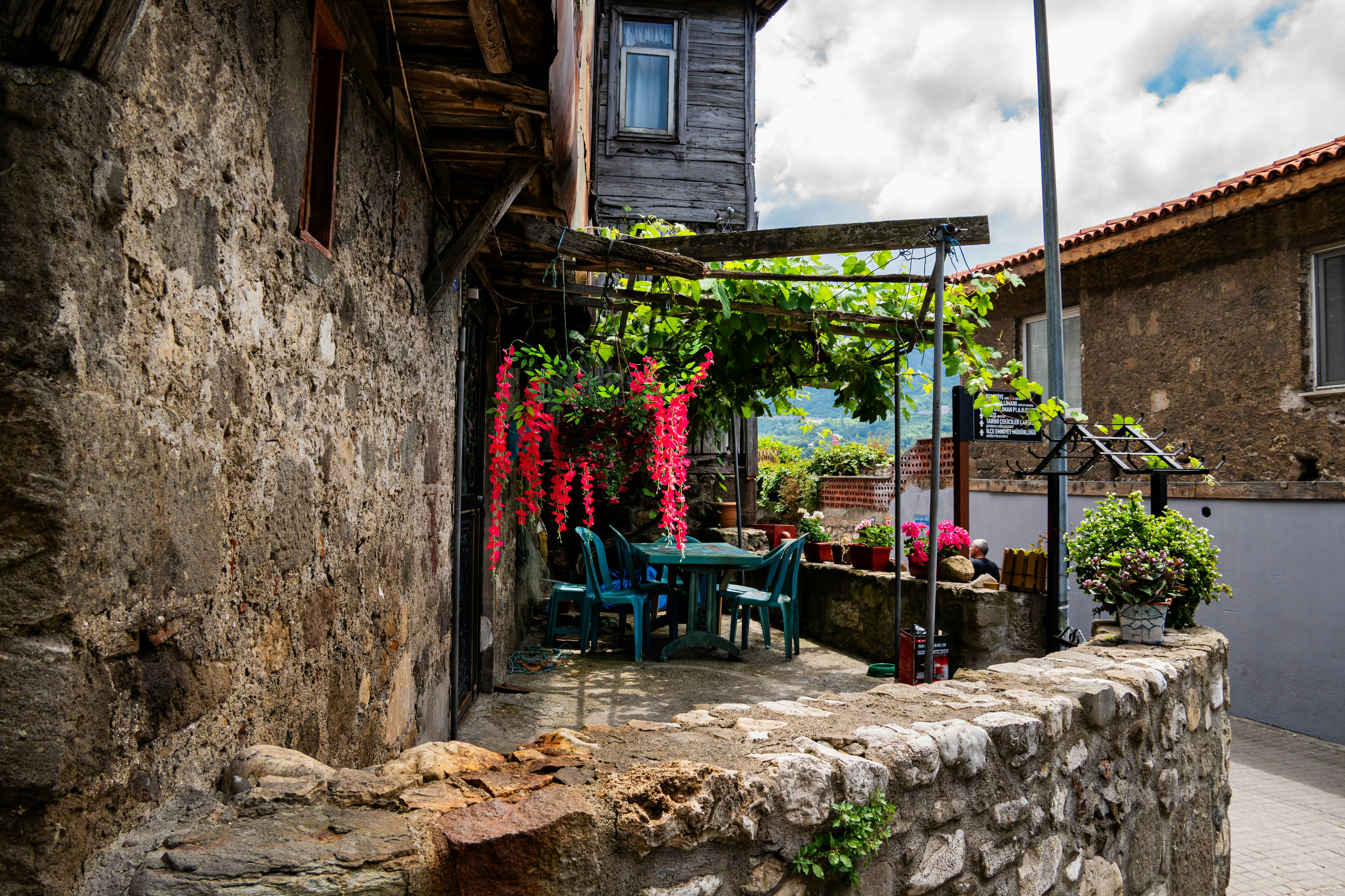 Sunlit courtyard with flowering trellis alongside weathered stone walls