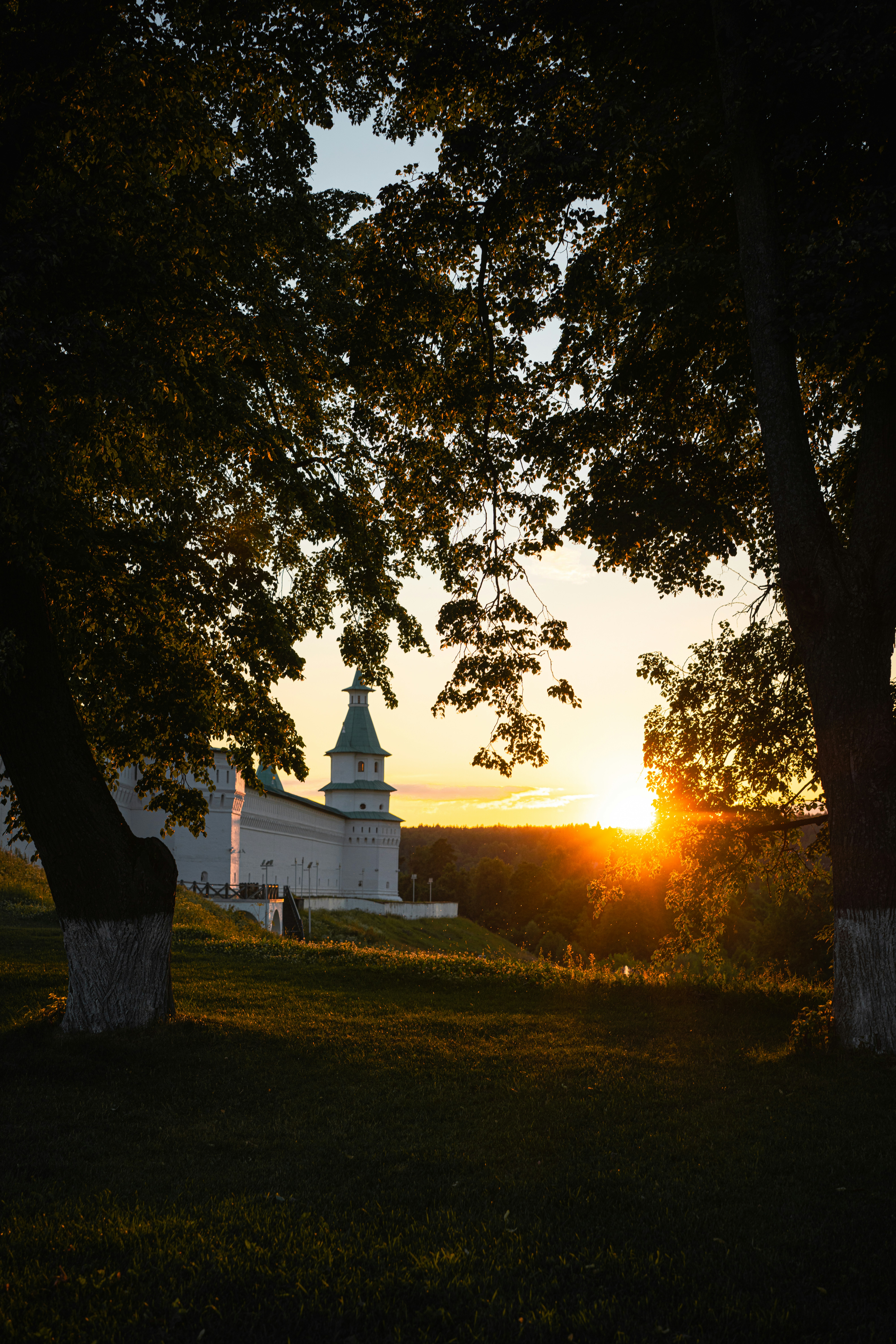 Sunlit Clearing with Historic White Structure Framed by Oaks