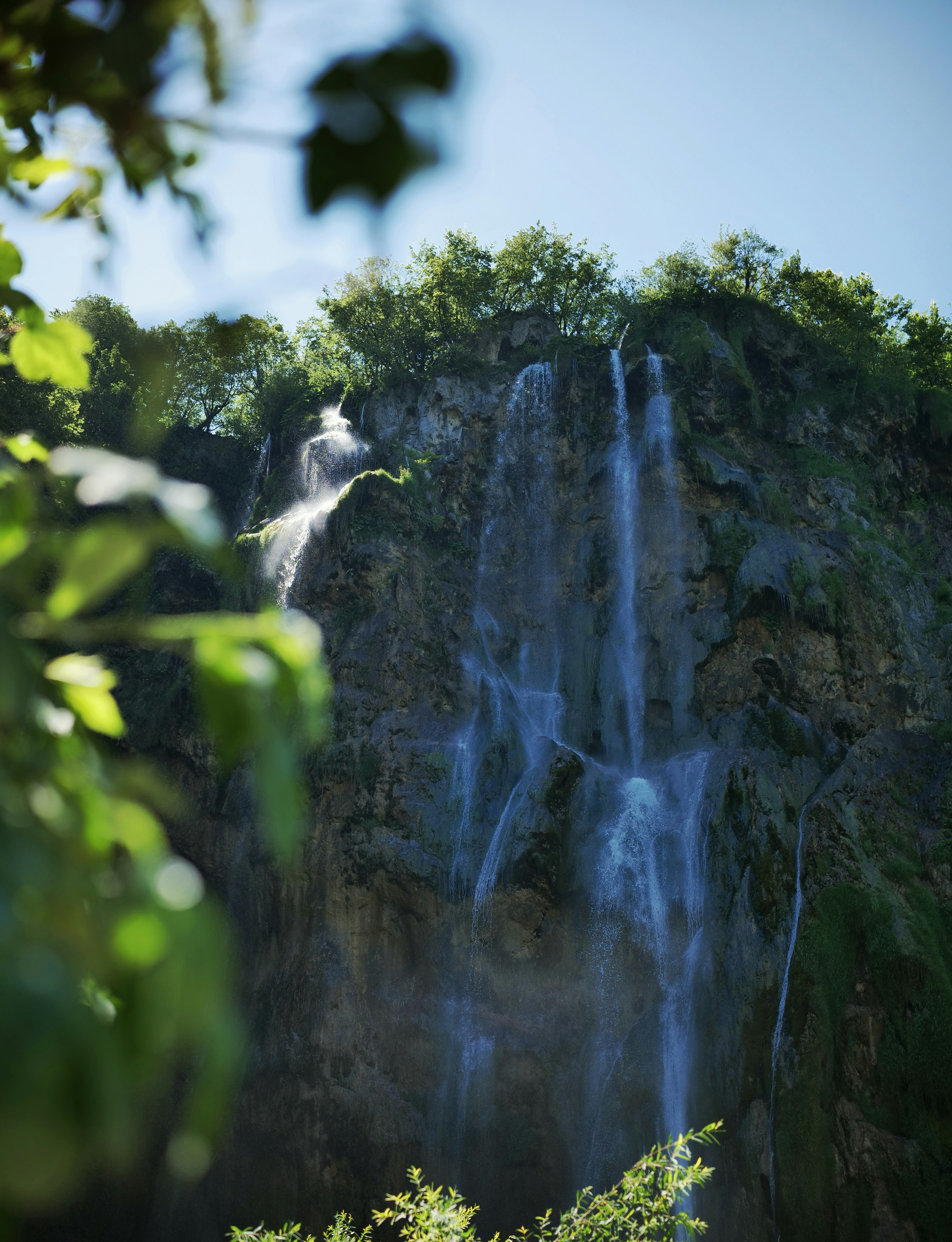 Cascading Veil: Sunlit Falls Against a Rugged Cliff