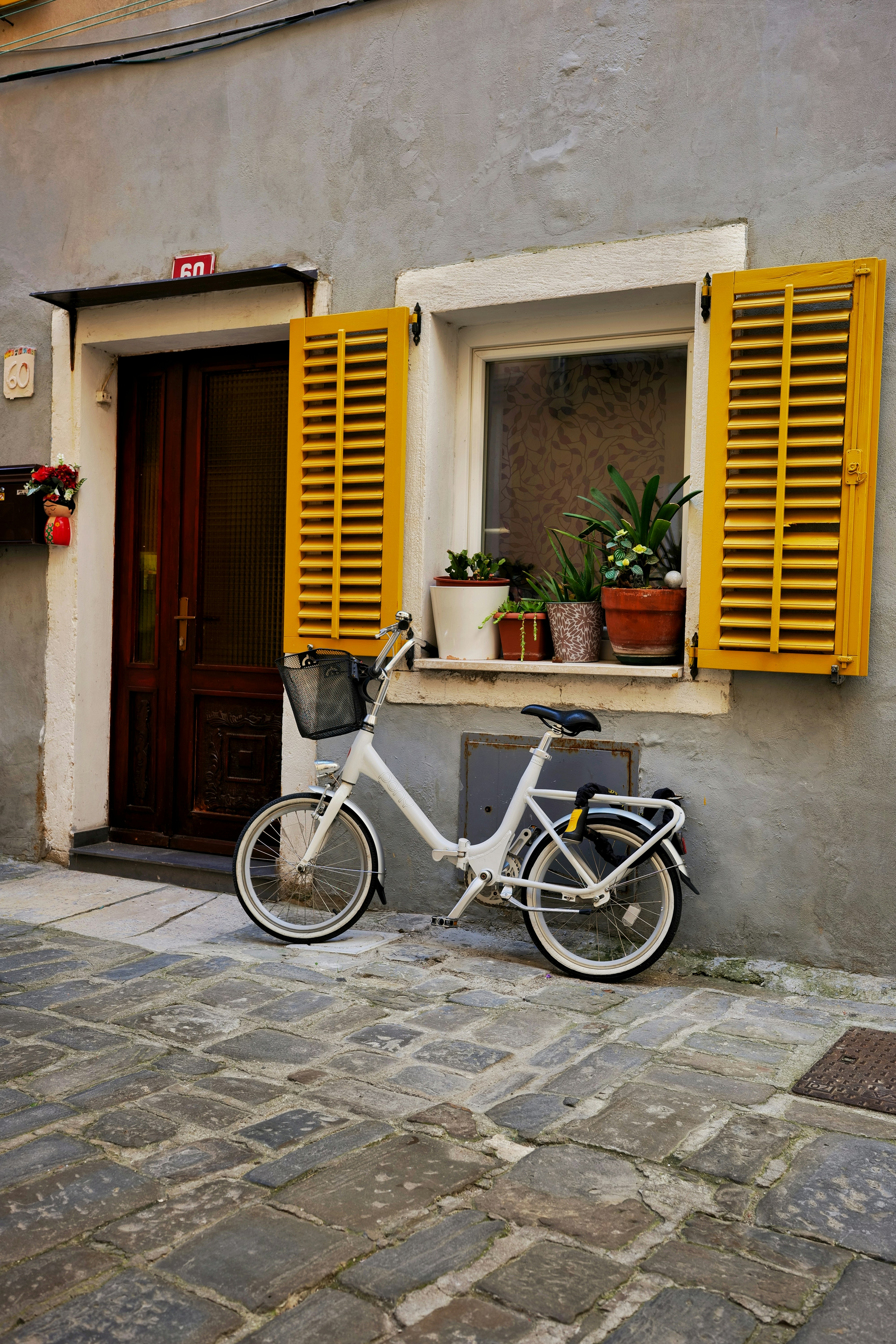 Yellow Shutters and White Bicycle on a Cobblestone Street