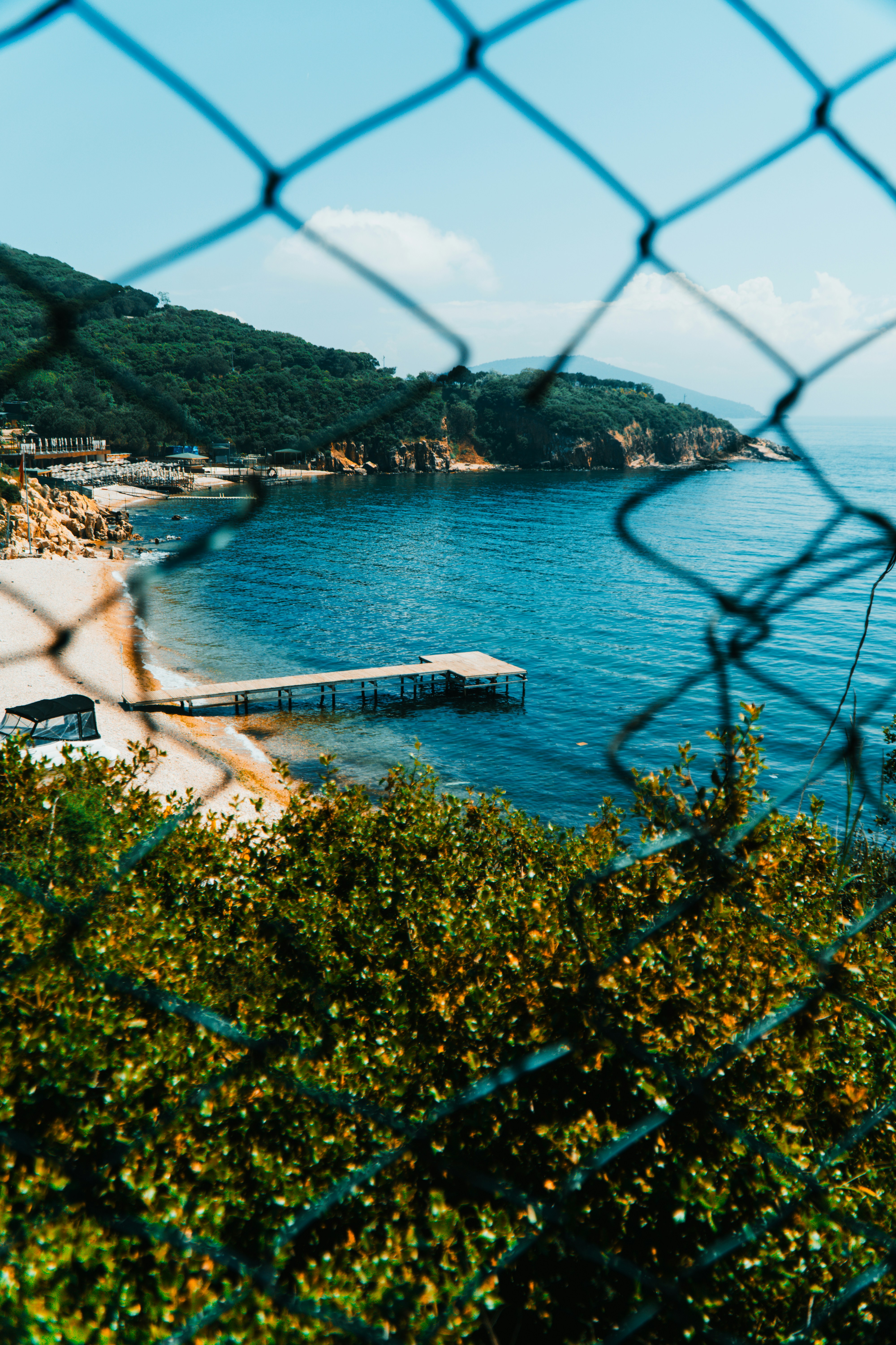 Chain-Link View: A Coastal Scene Framed by a Fence