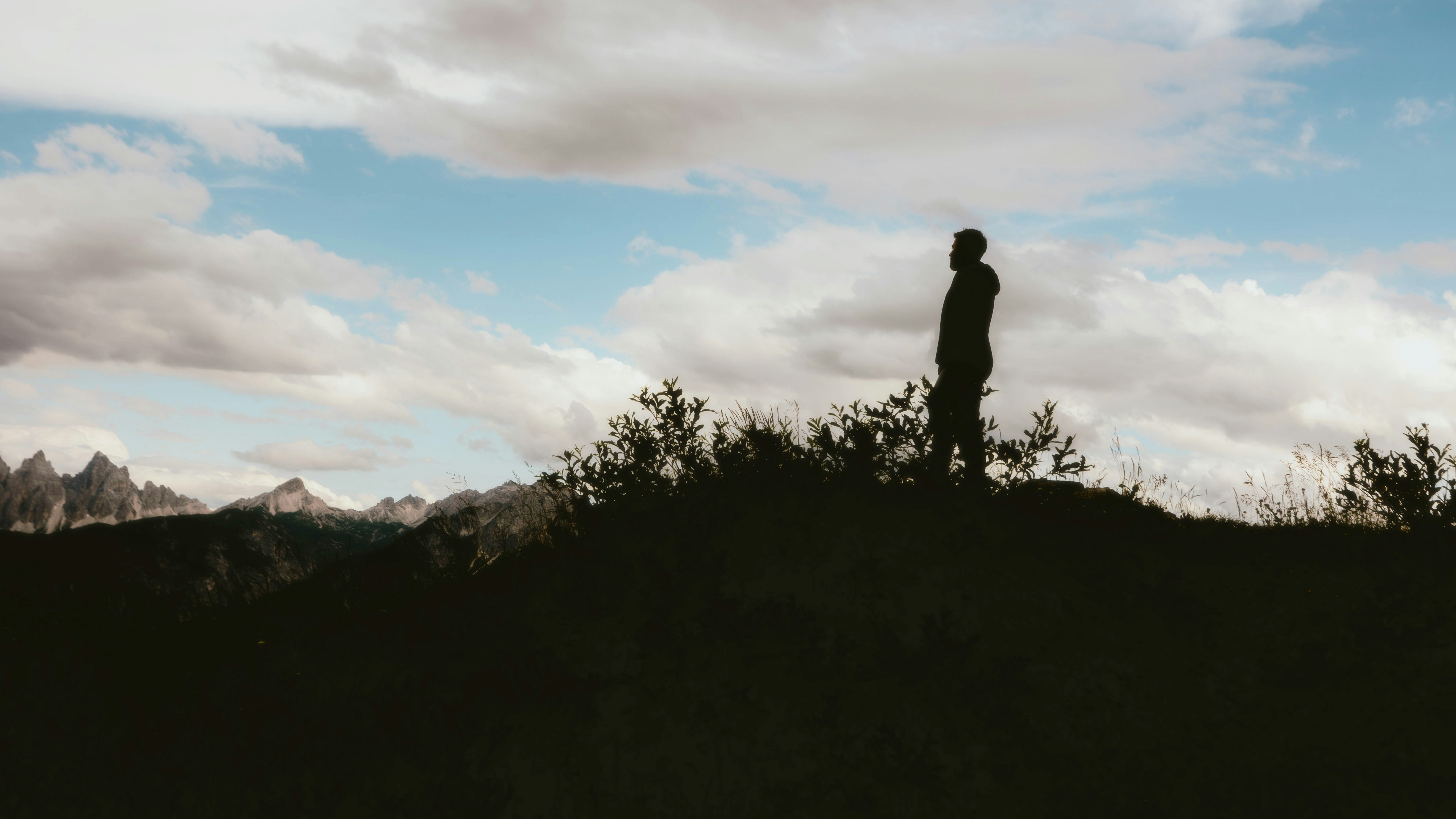 Silhouette on the Ridge: A Lone Figure Against a Sky of Soft Cumulus