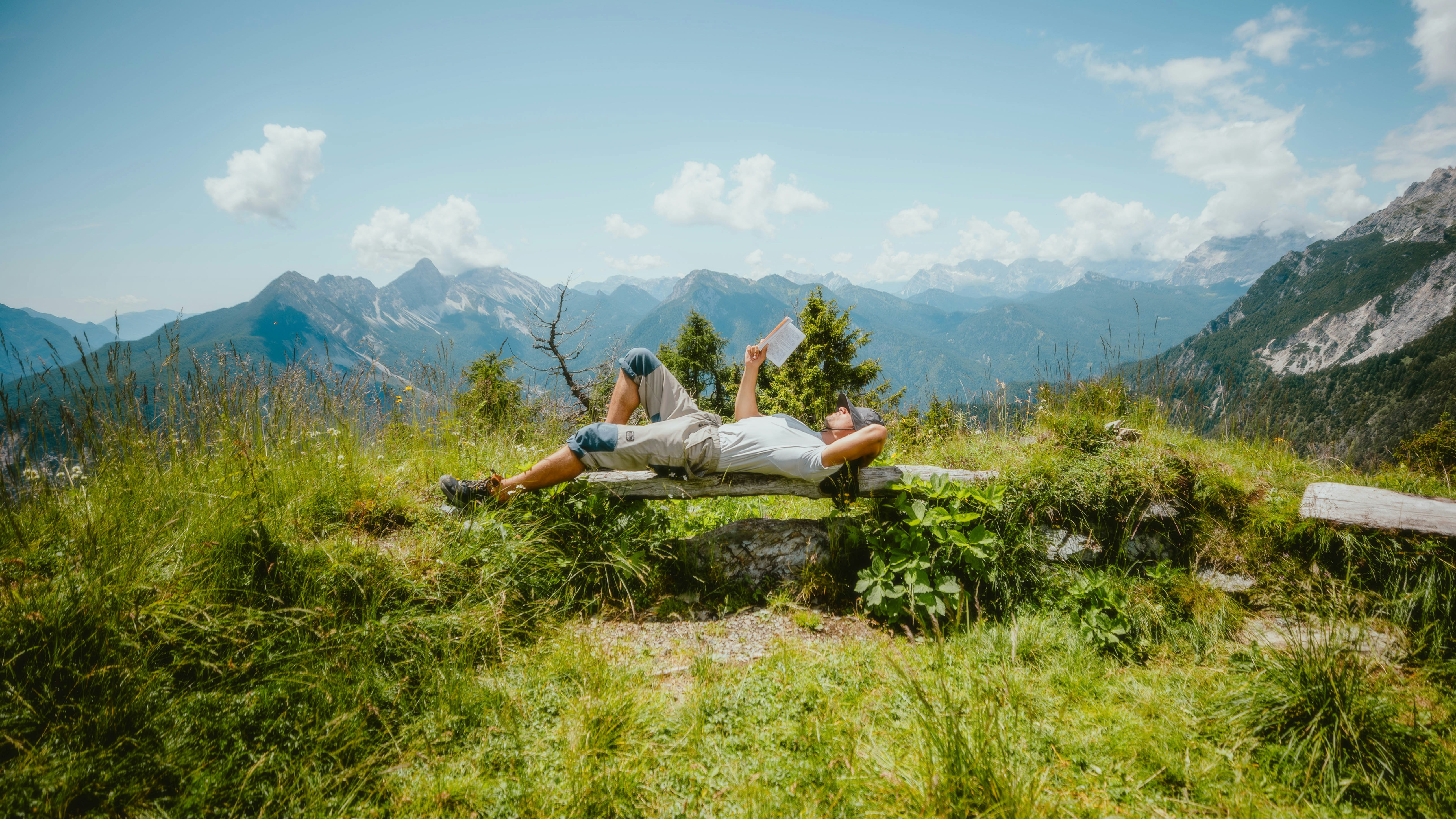 Lounge on a Alpine Knoll: Resting Traveler Amid Soaring Peaks