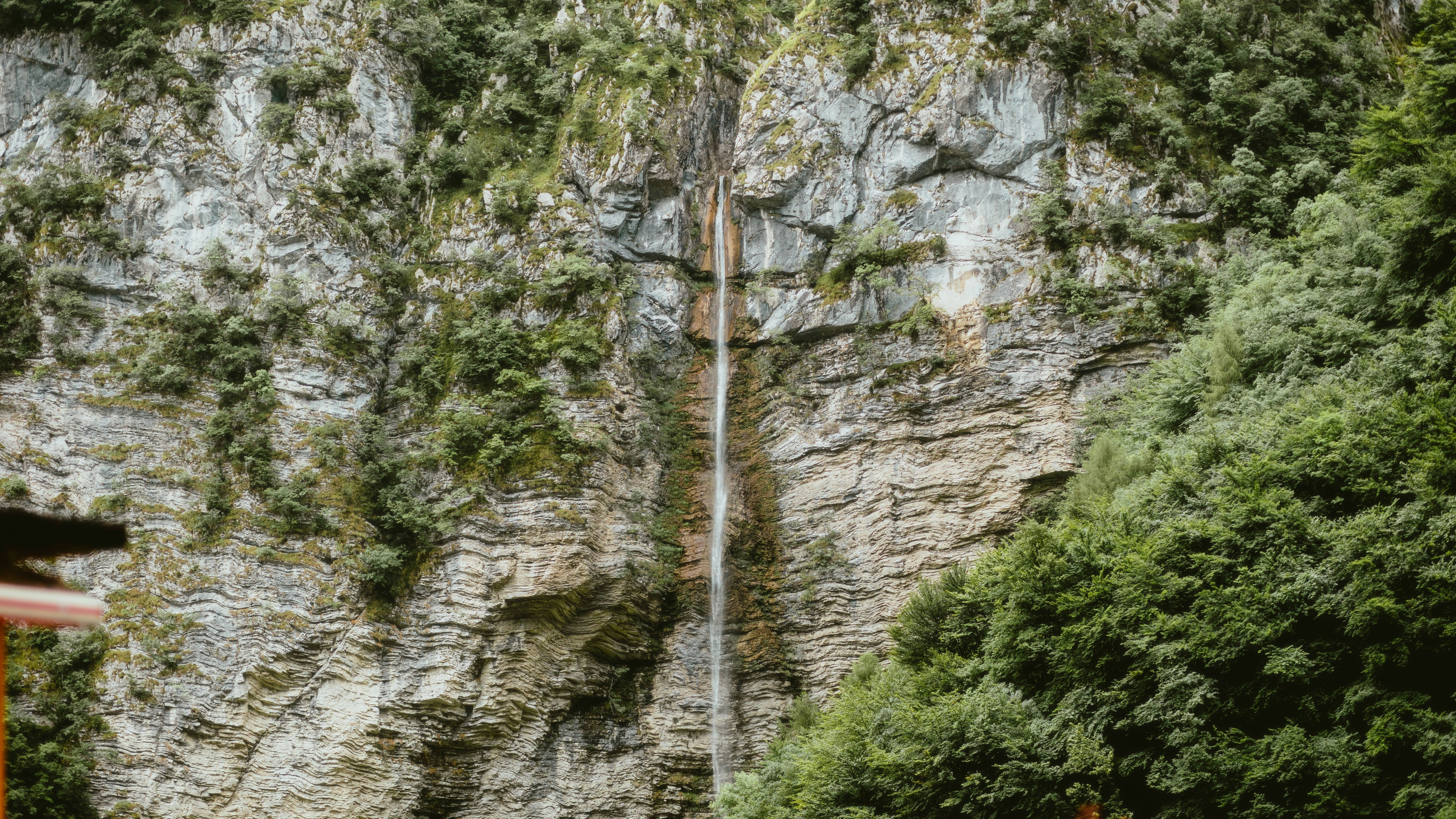 Vertical Climb: A Thin Cascade Beckons Against a Rugged Cliff