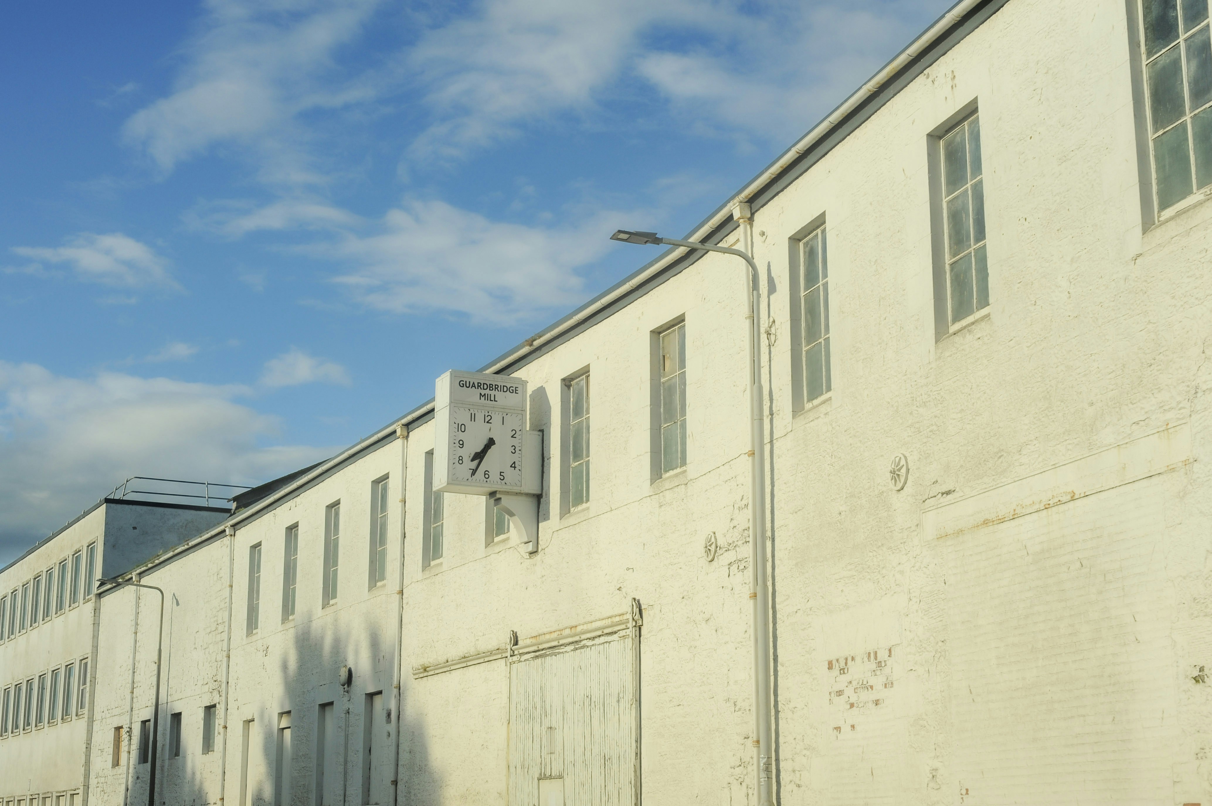 Sunlit Warehouse Facade under a Patchwork of Clouds