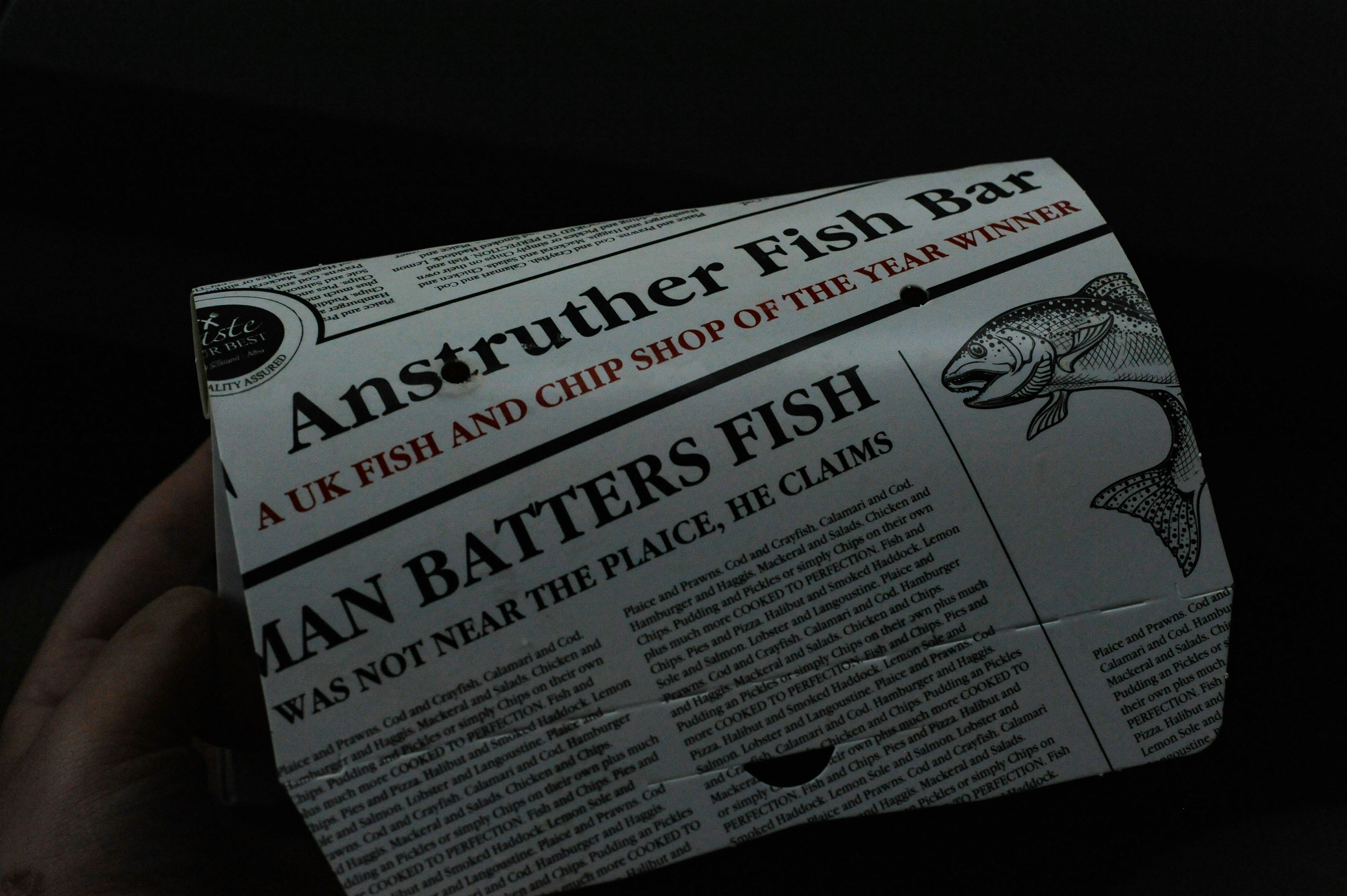Newspaper-wrapped lunch box under dim light