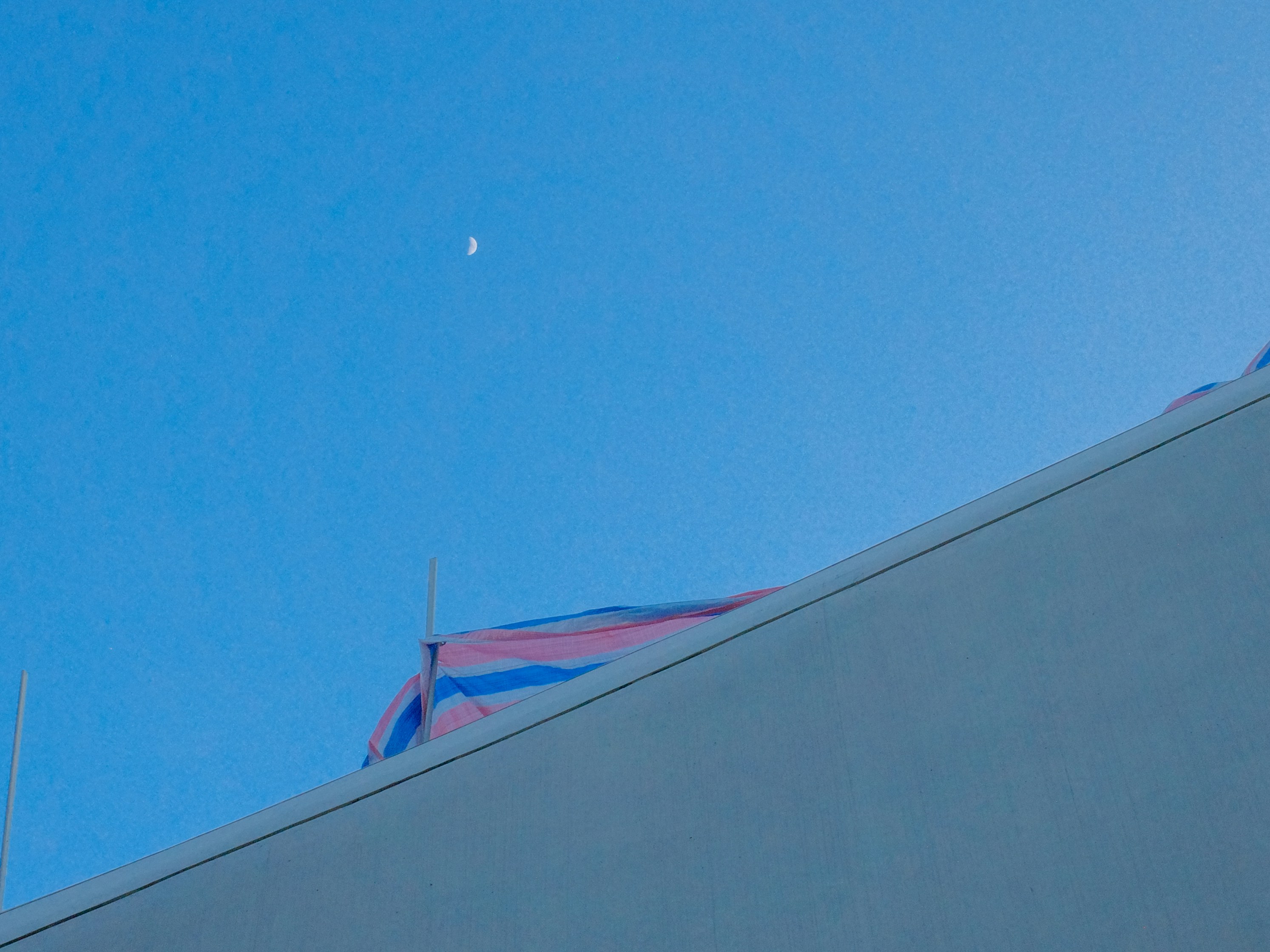 Blue Sky Over a Slanted Roof with a Multi-Color Flag
