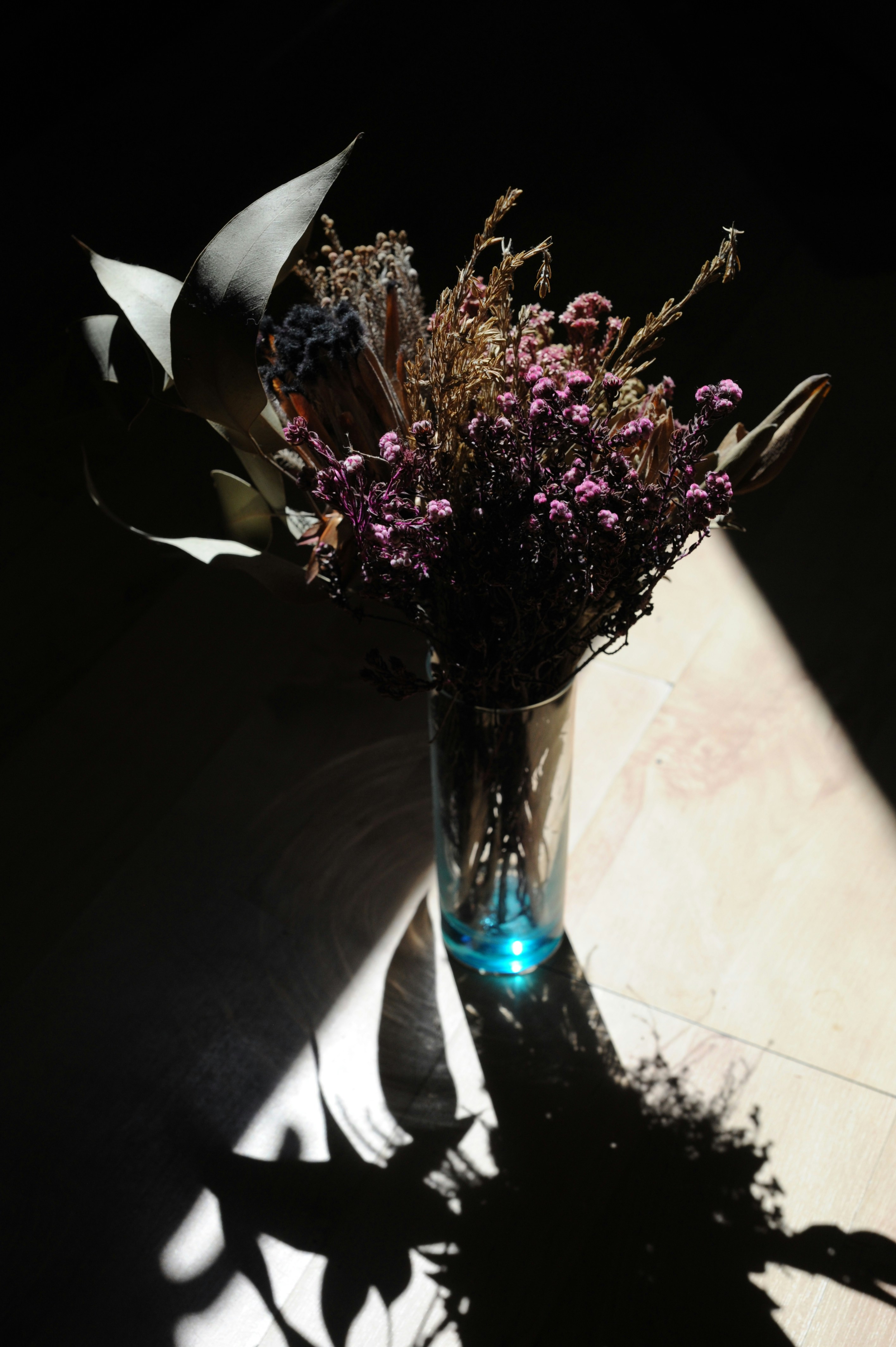 Dried bouquet in a glass vase bathed in dramatic light