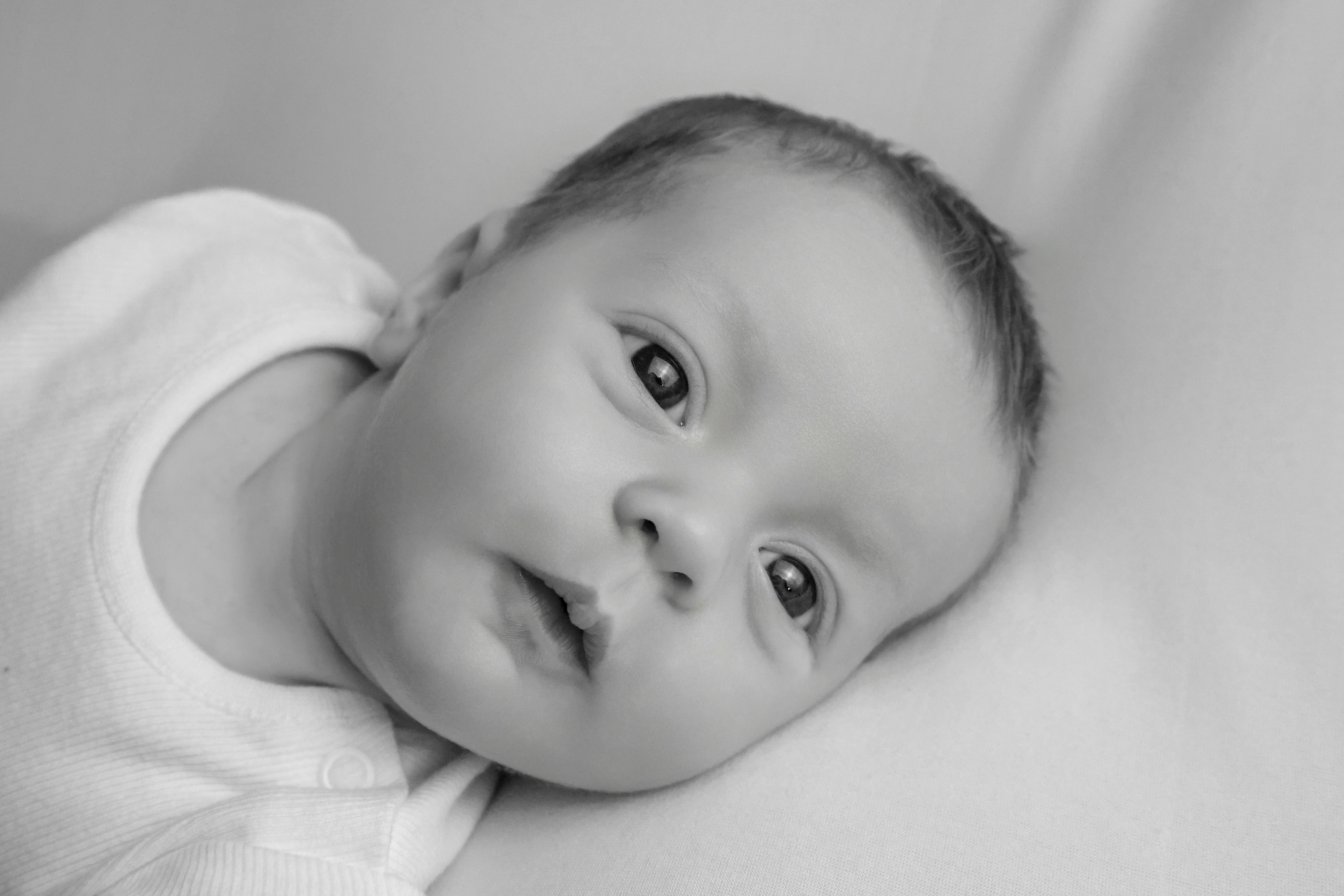 Soft Gaze: A Baby's Quiet Moment on a Cream Fabric Surface