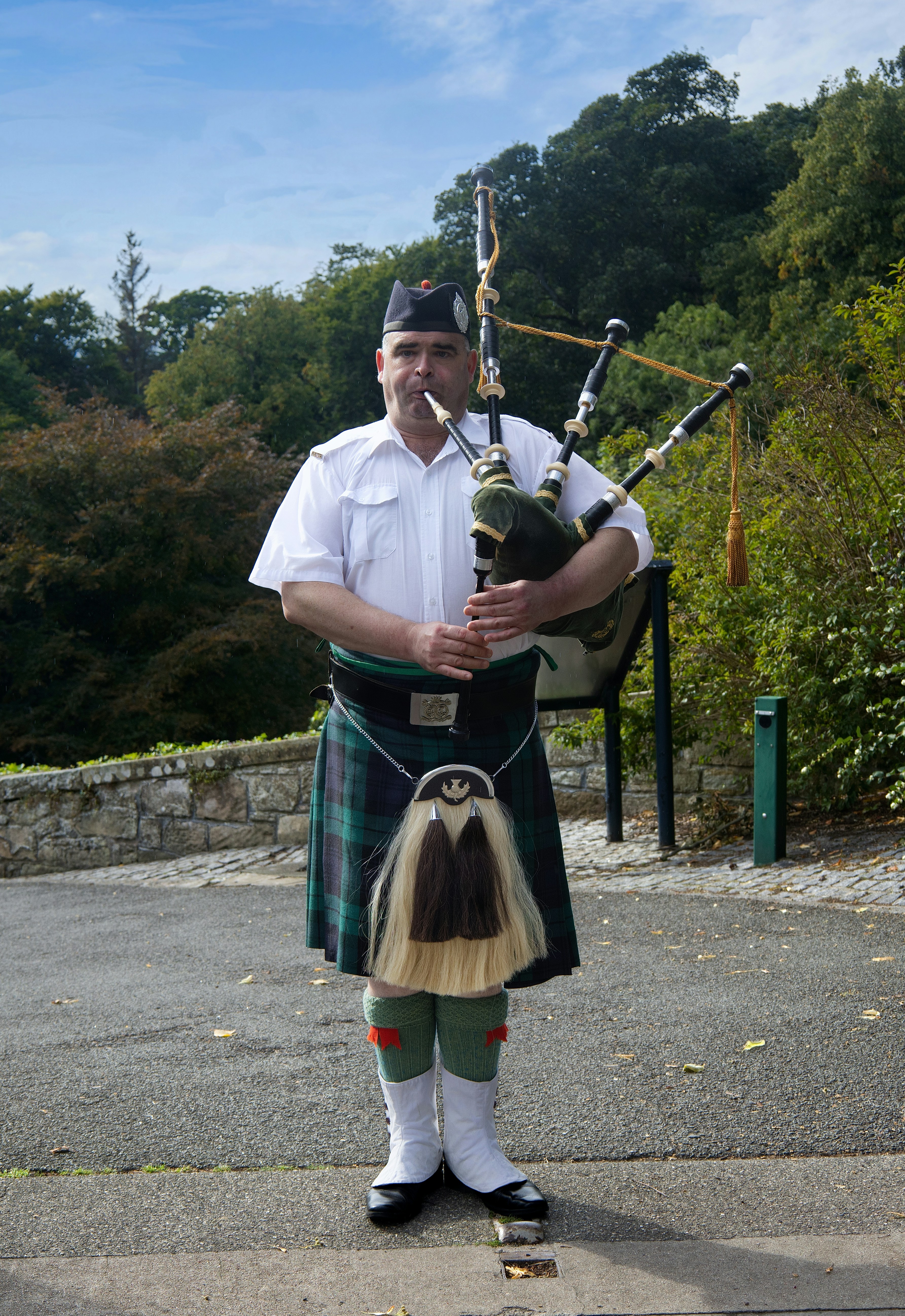 Bagpiper in Traditional Dress at a Scenic Park