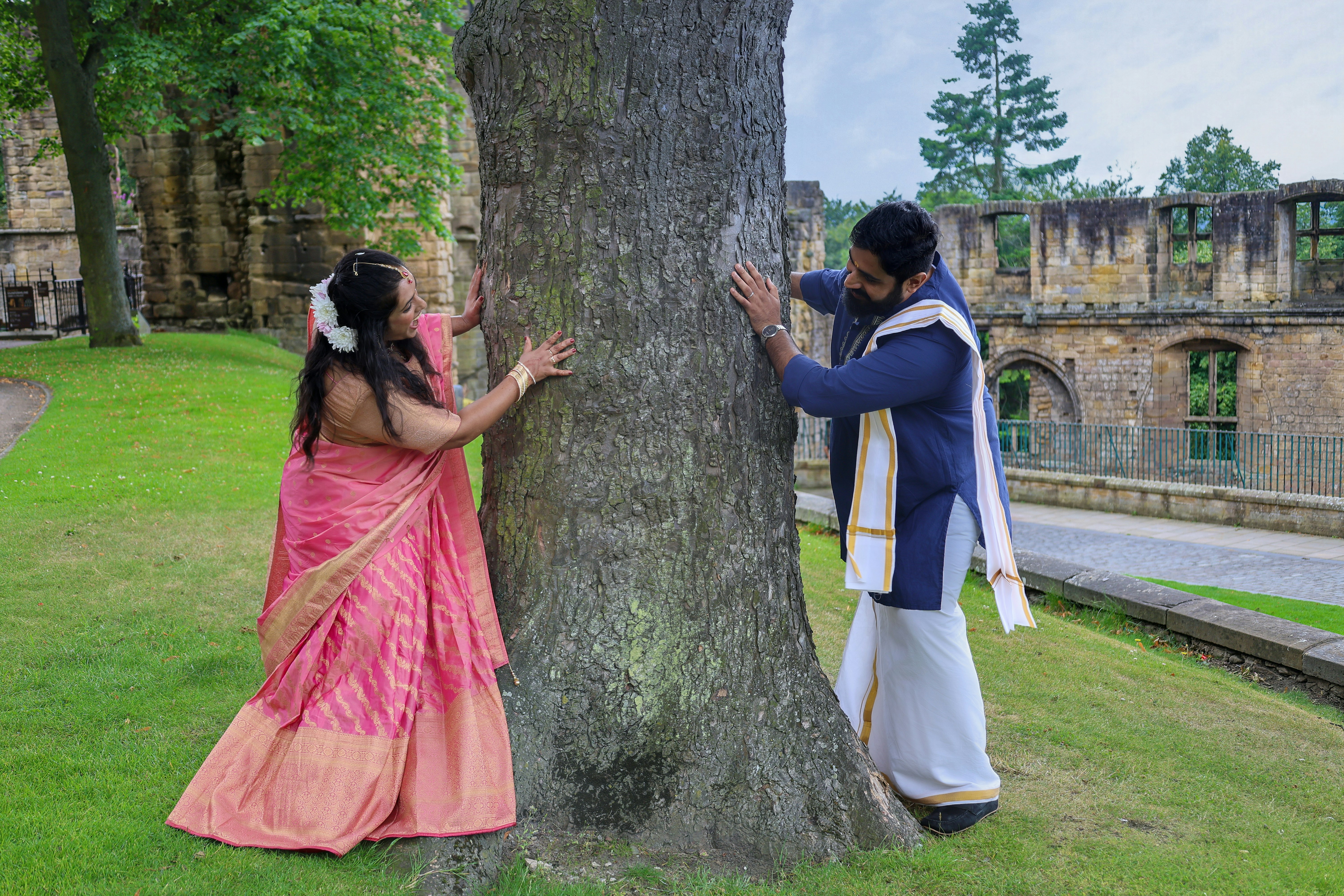 Duo in Traditional Attire Embrace a Century-Old Tree Toward a Sunny Courtyard