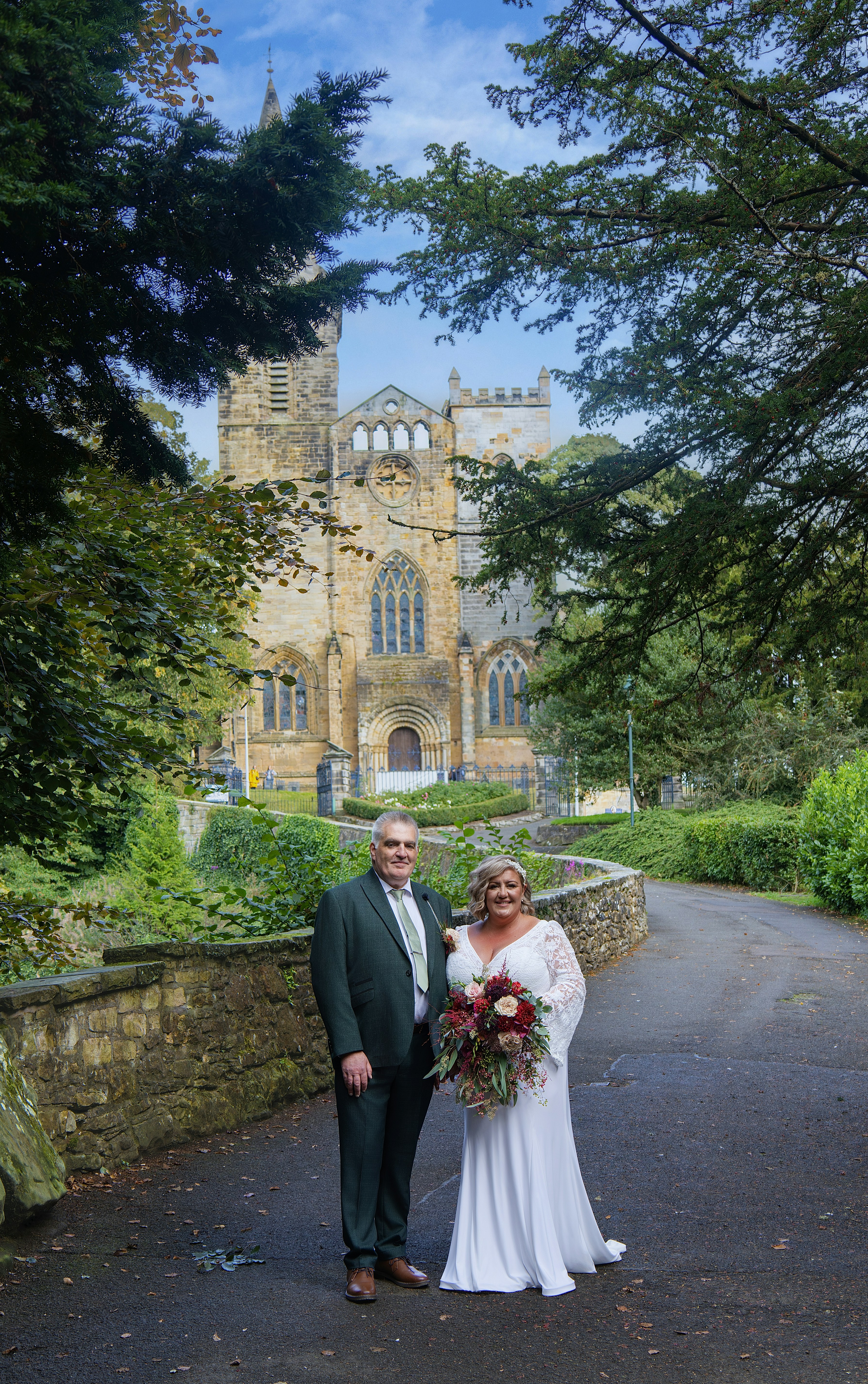 Bride and Groom Stand Before a Historic Abbey Gate