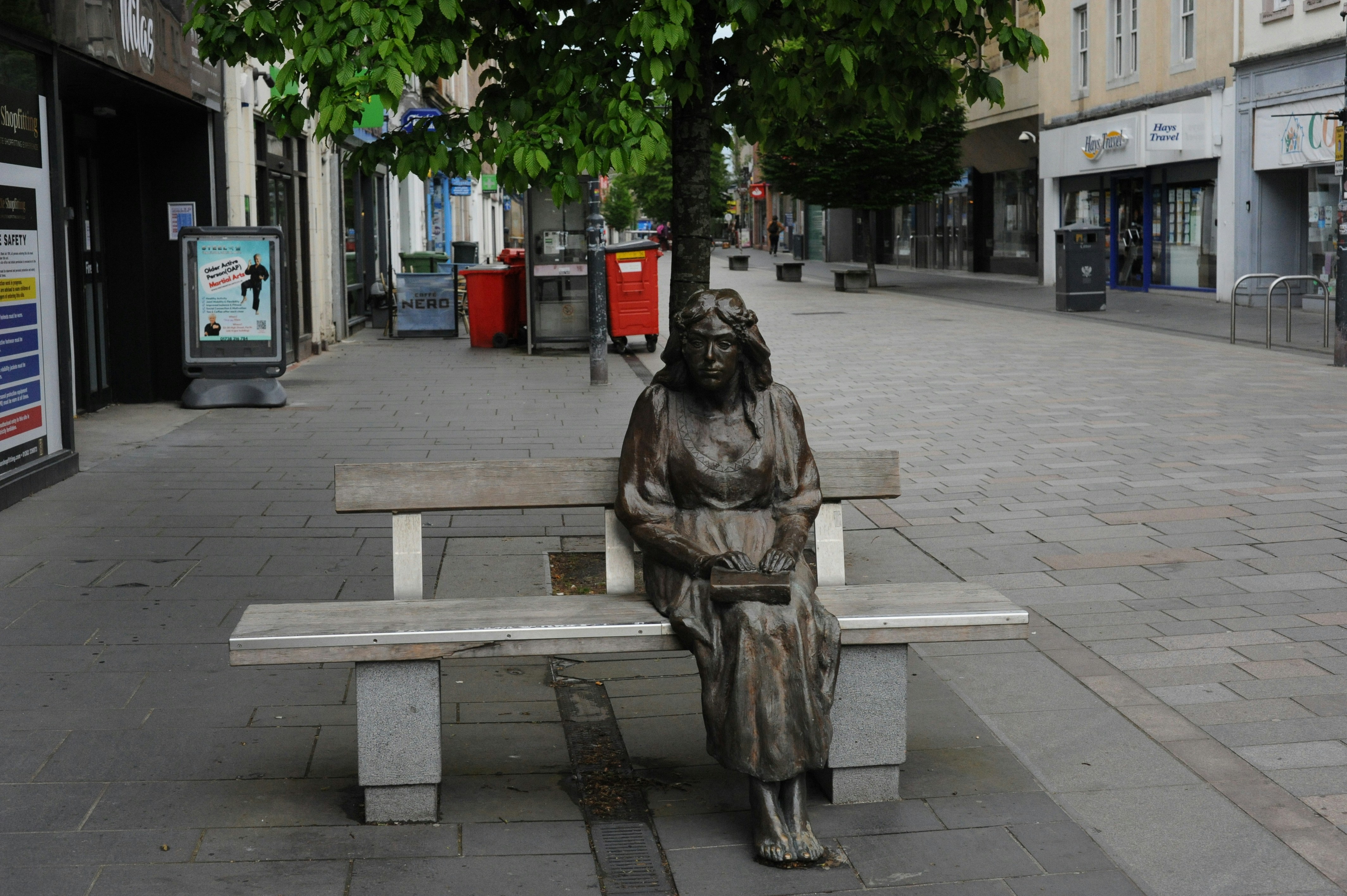 A Quiet Moment on a City Bench: Bronze Figure and Streets Ahead