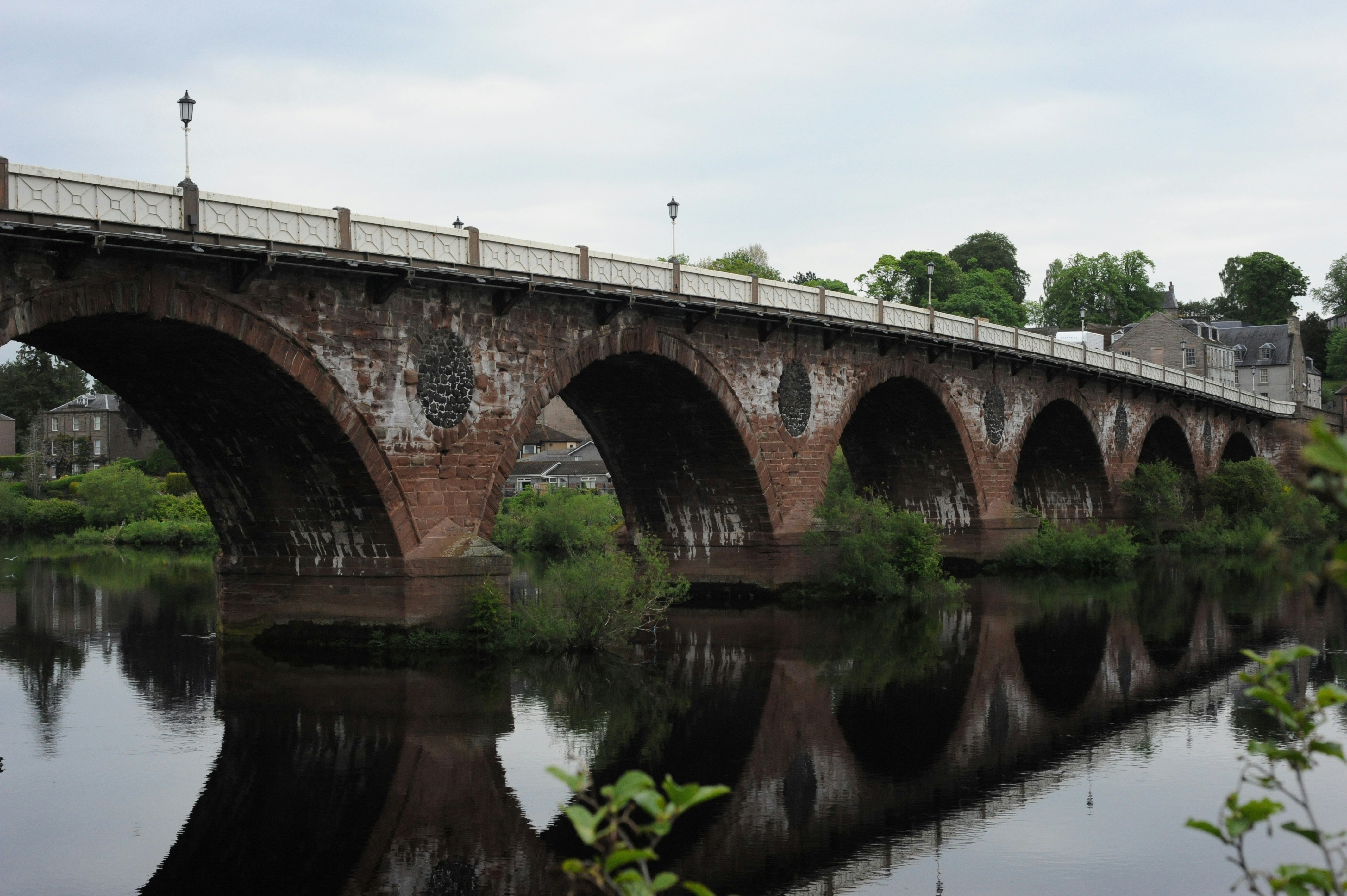 Reflected Arches: A Brick Bridge Framed by River Quietude