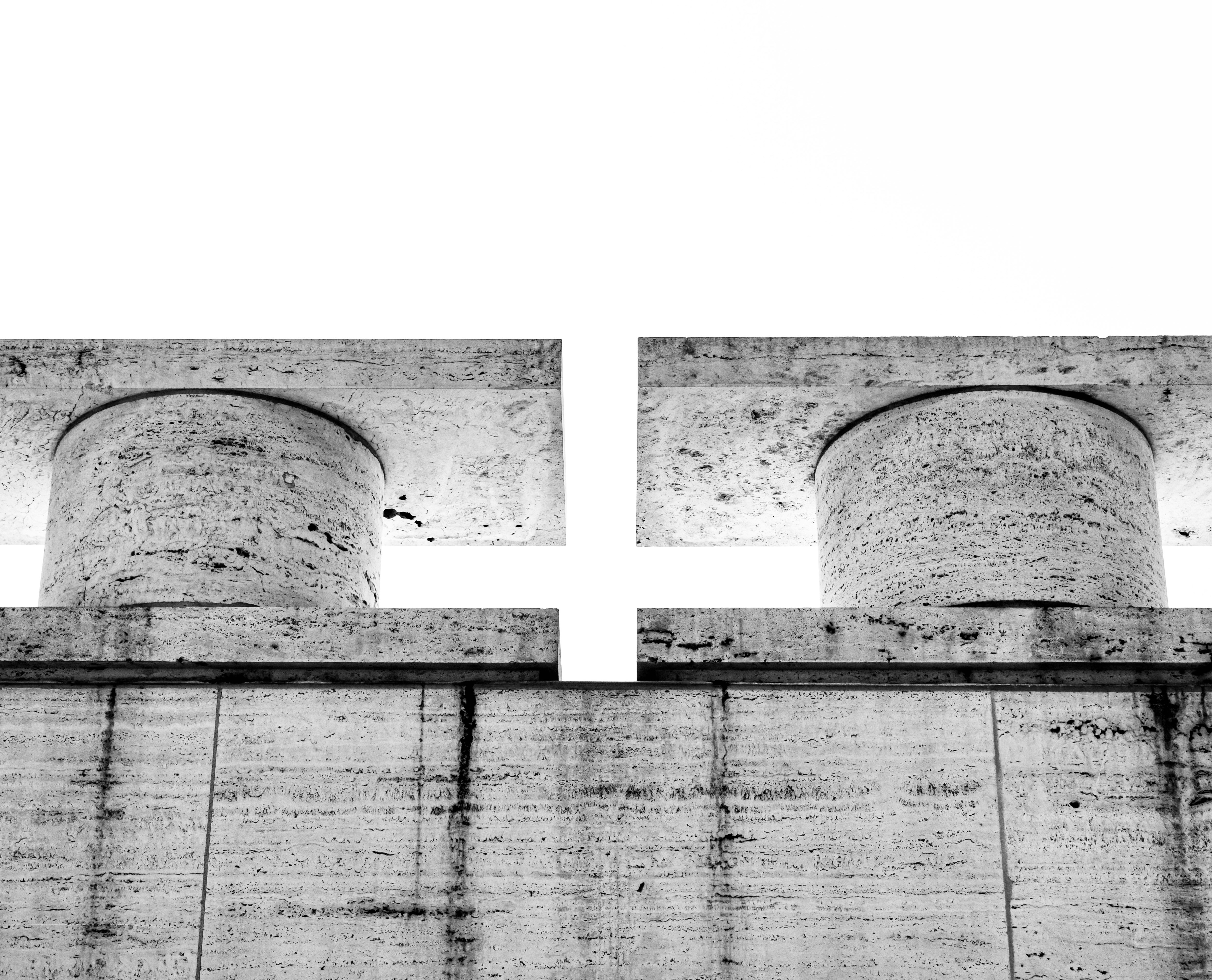 Twin Concrete Cylinders Against Aged Plinth