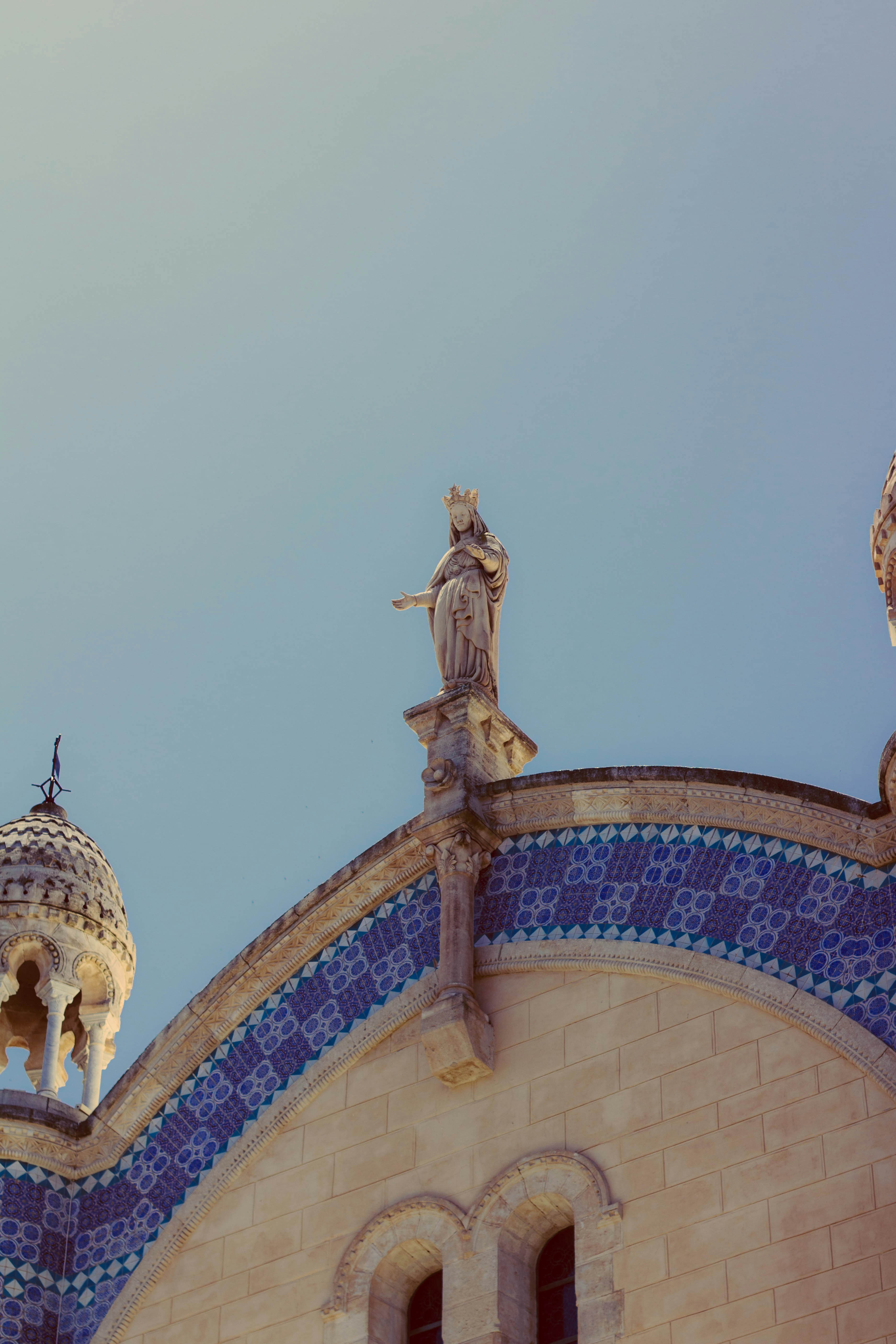 Statue Above the Mosaic Arch: A Cathedral Roofline under Clear Sky