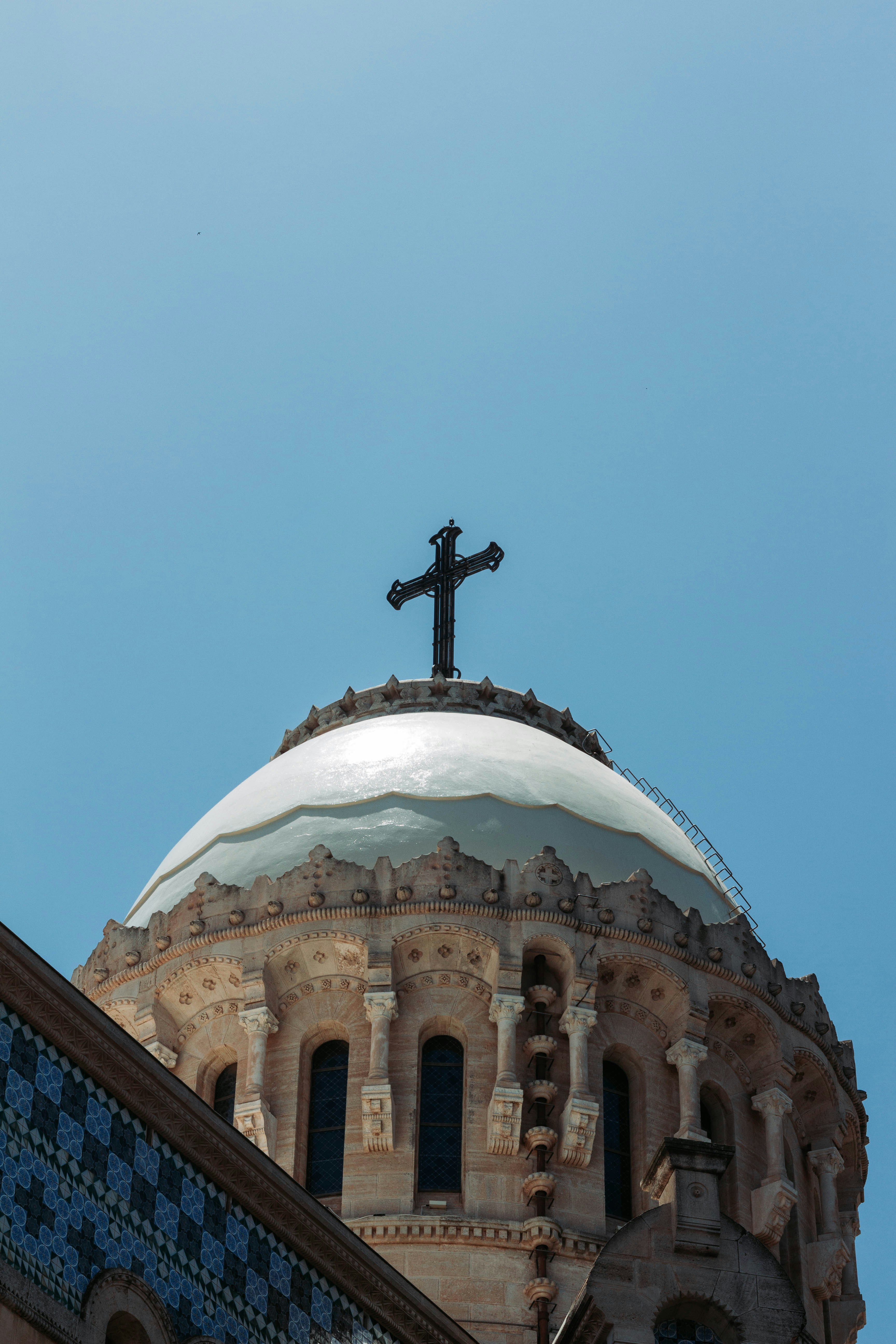 Cross atop a domed facade crowned by a clear blue sky
