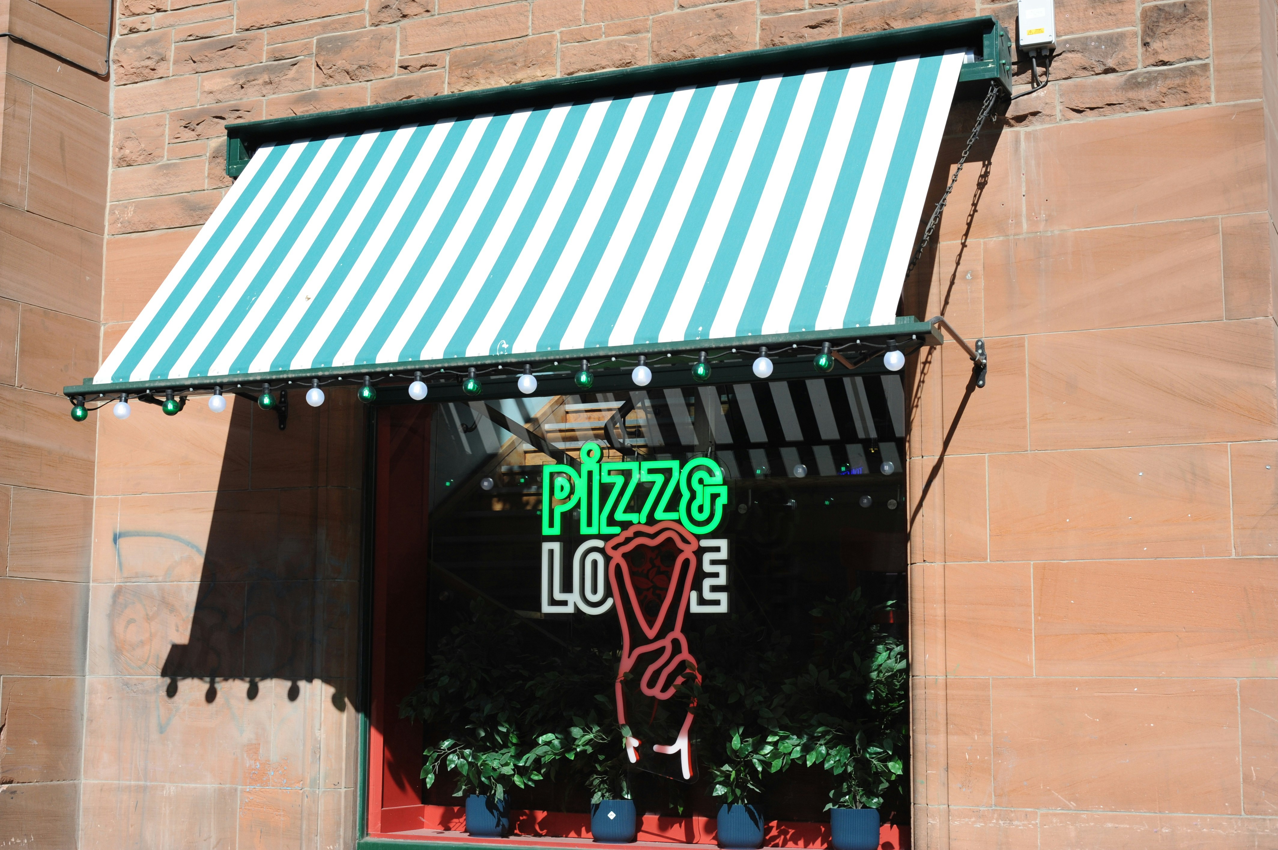 Striped awning over neon pizza parlor sign