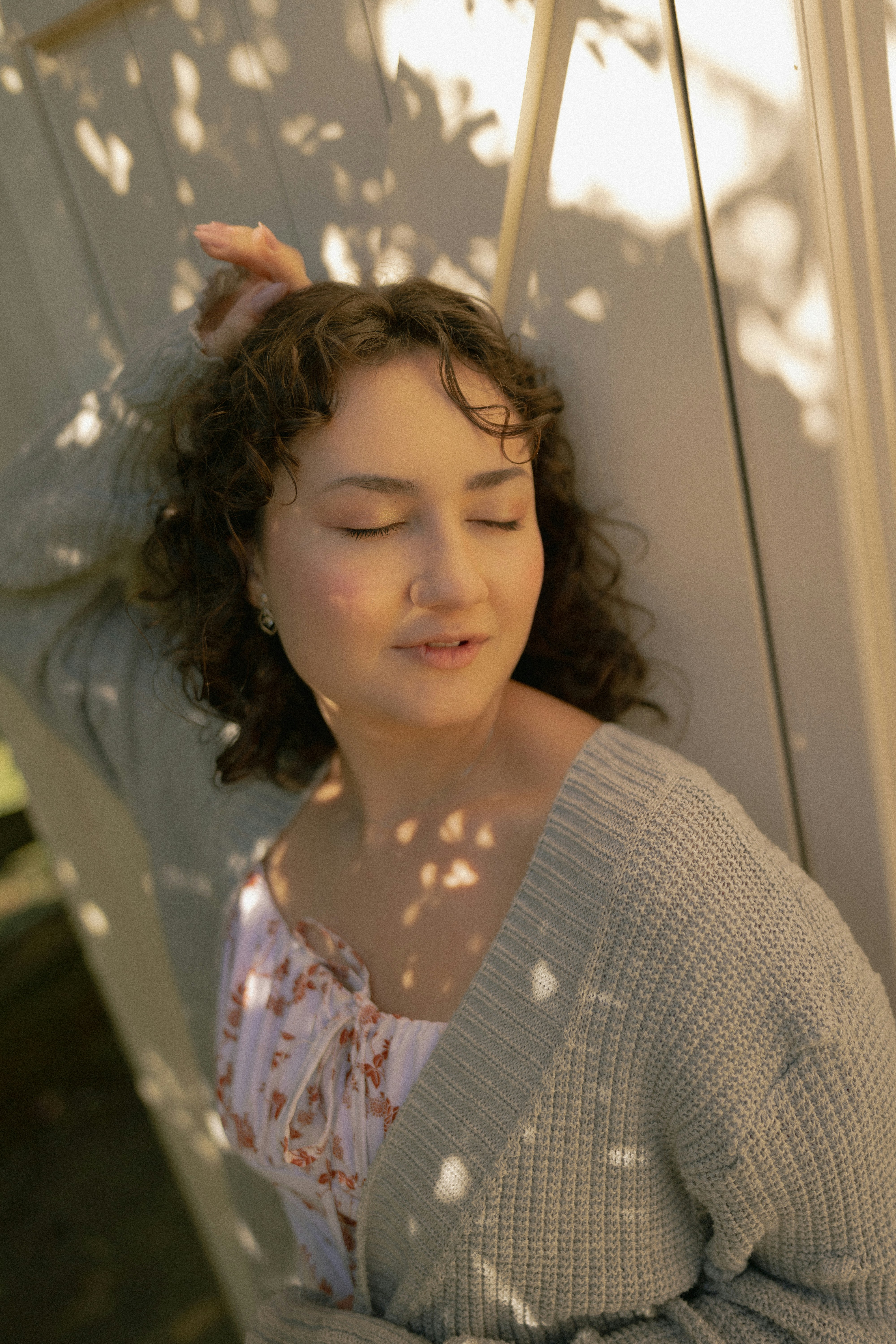 A young woman with closed eyes in dappled sunlight.
