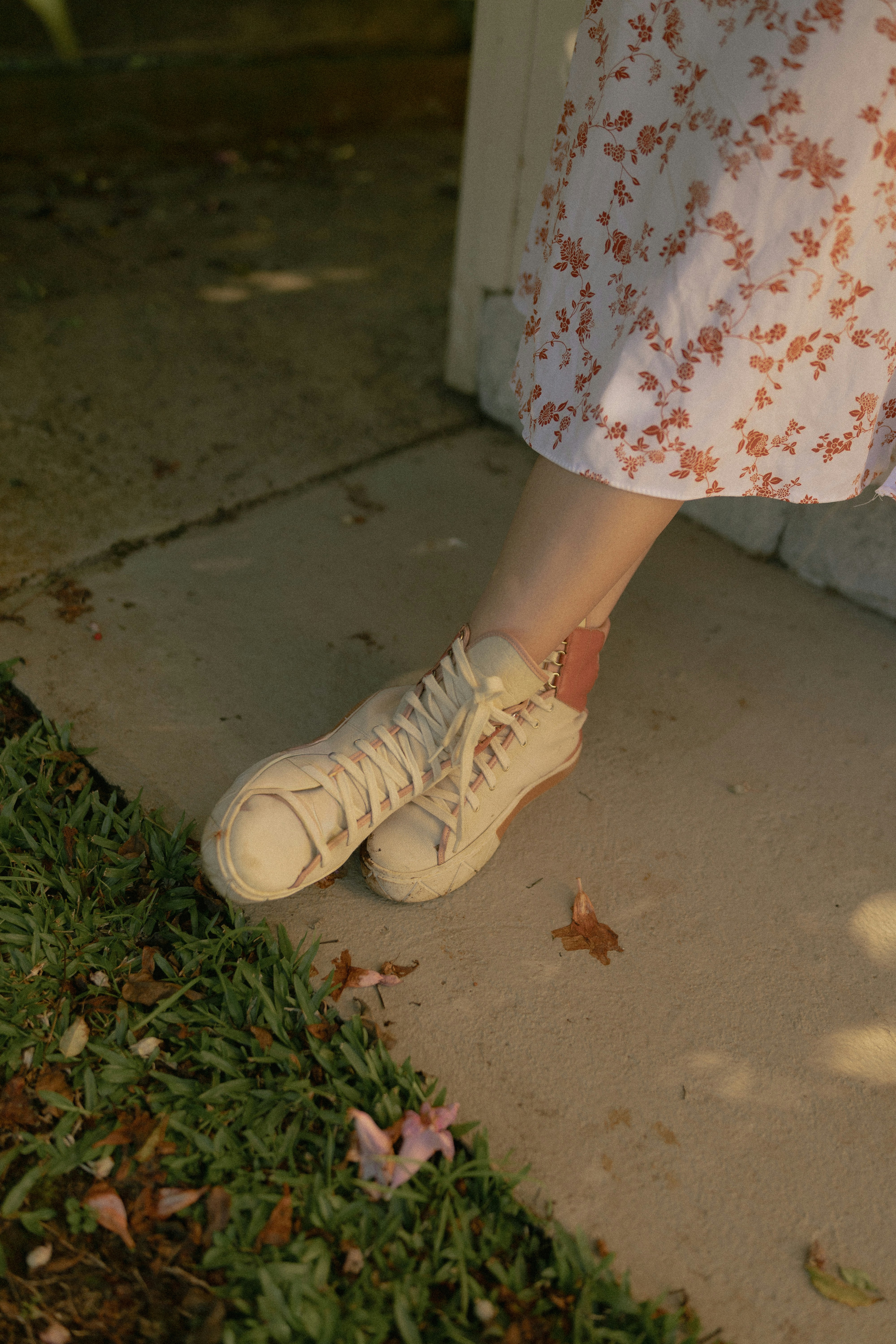 Barefoot Seaside Steps: Floral Hem and Cream Sneakers on Concrete