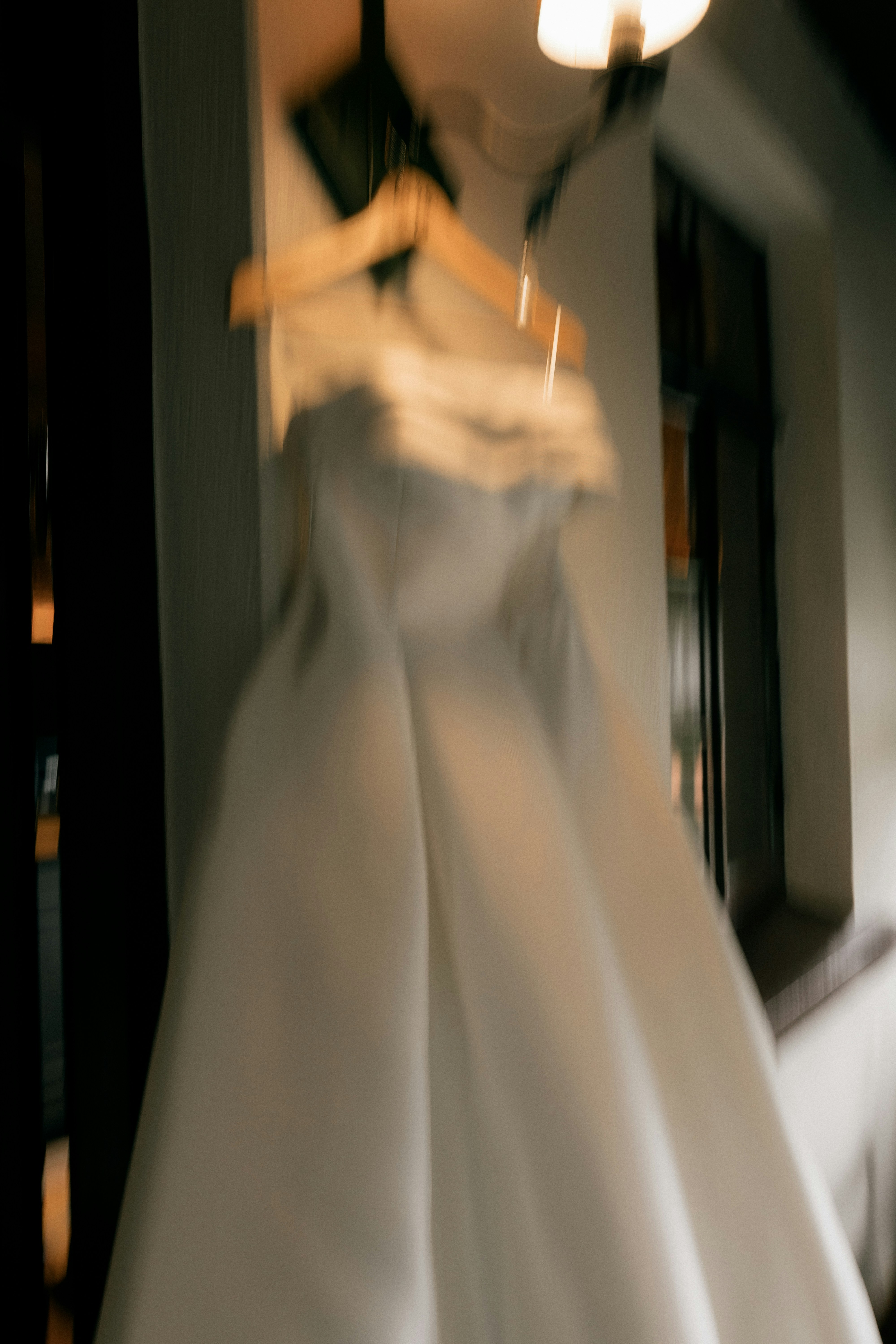 Hanging Promise: A Blurred Gown on a Quiet Wardrobe Night