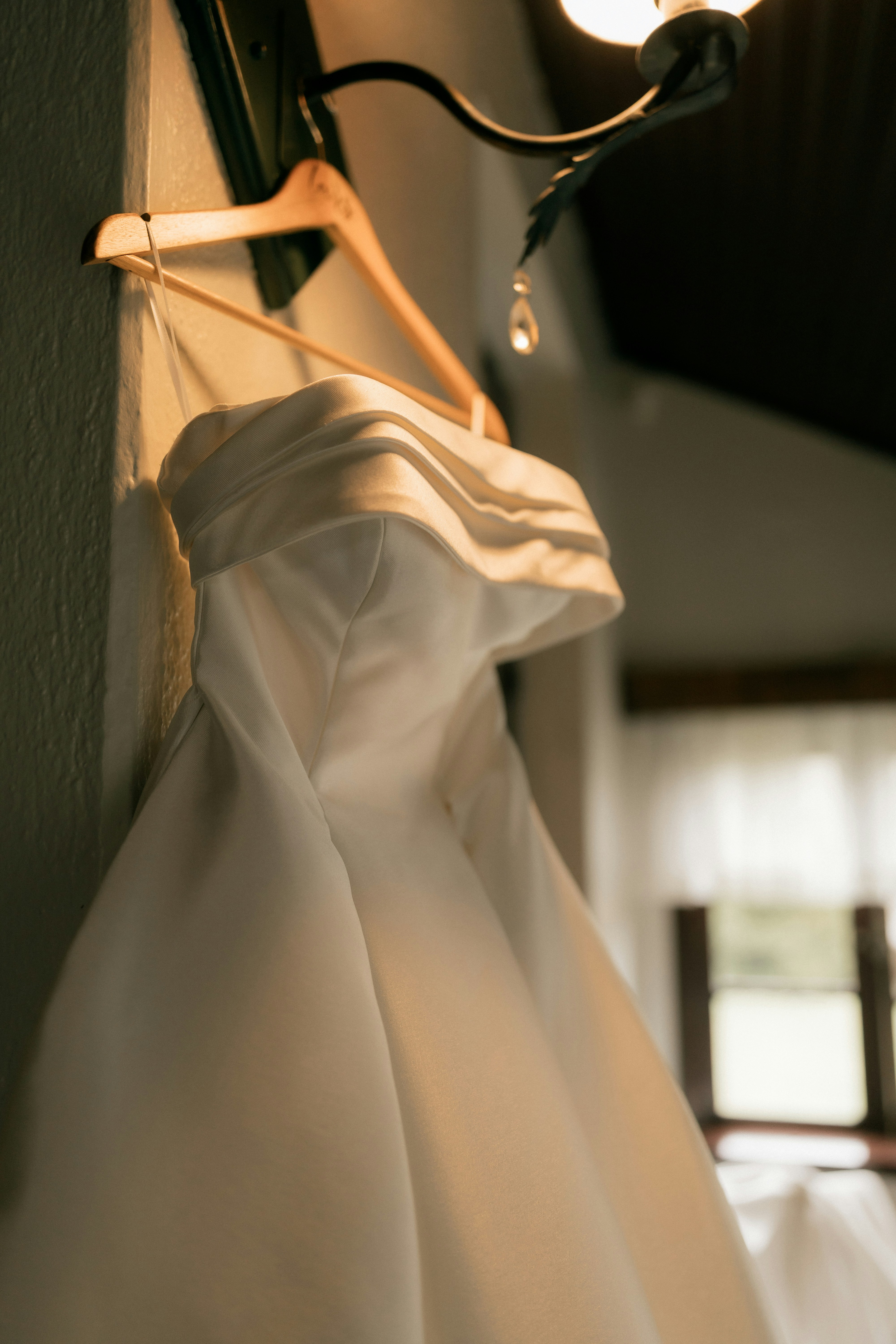 White Wedding Dress Draped on a Hanger in Soft Indoor Light