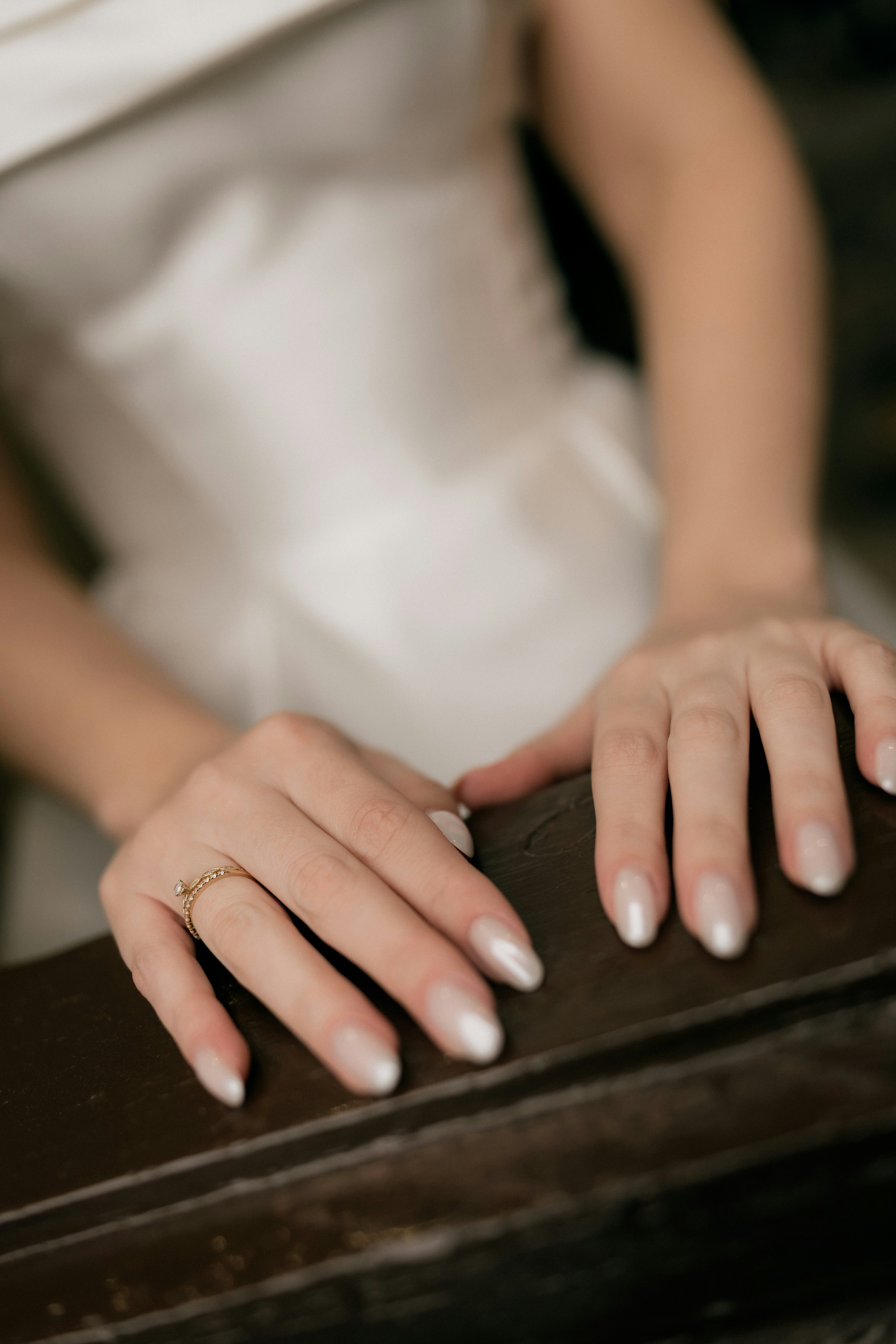 Bride’s Hands Resting on Dark Wood, Subtle Wedding Ring in Focus
