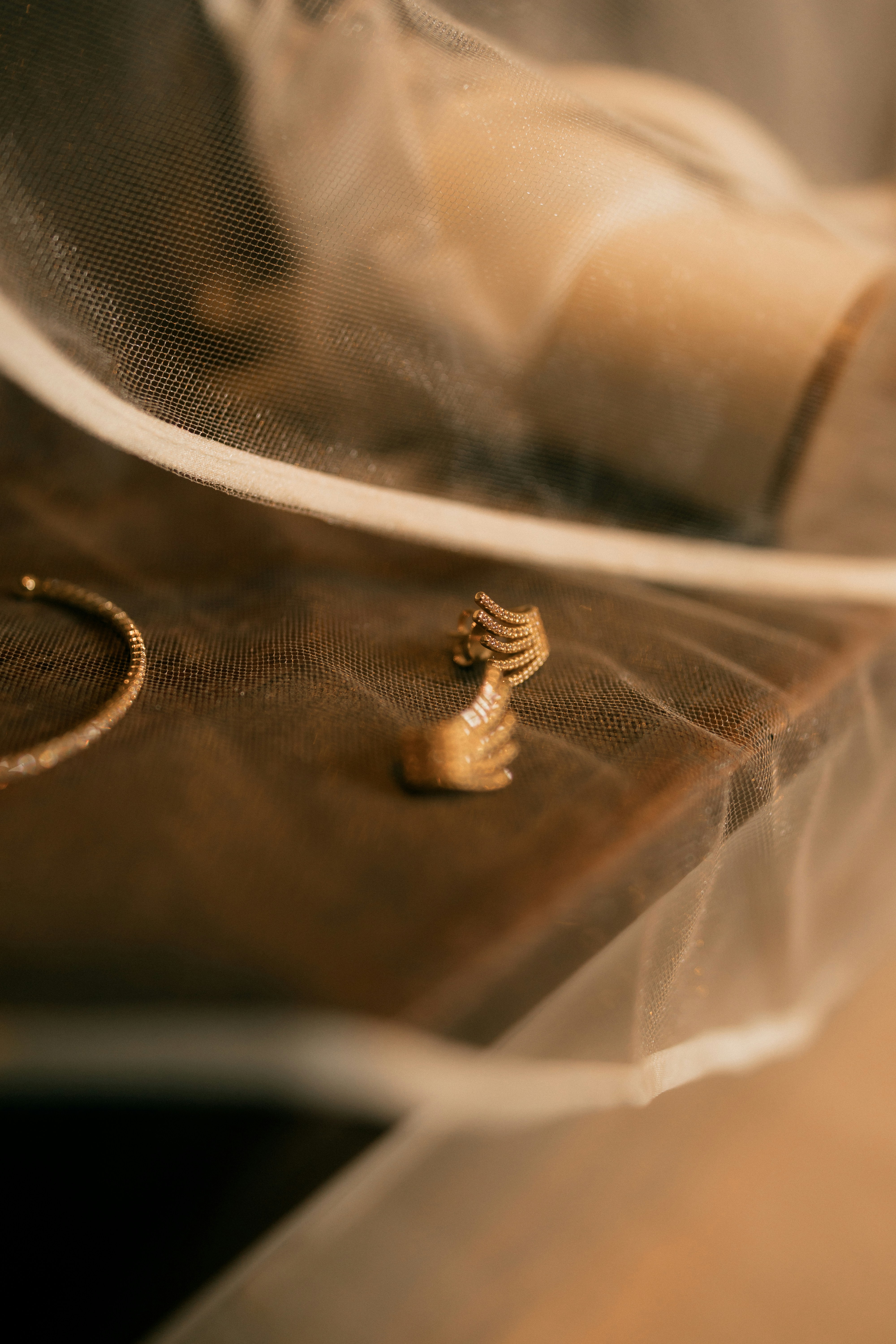 Gilded Jewelry in Soft Veil: Jewelry Pieces Resting Under Delicate Netting