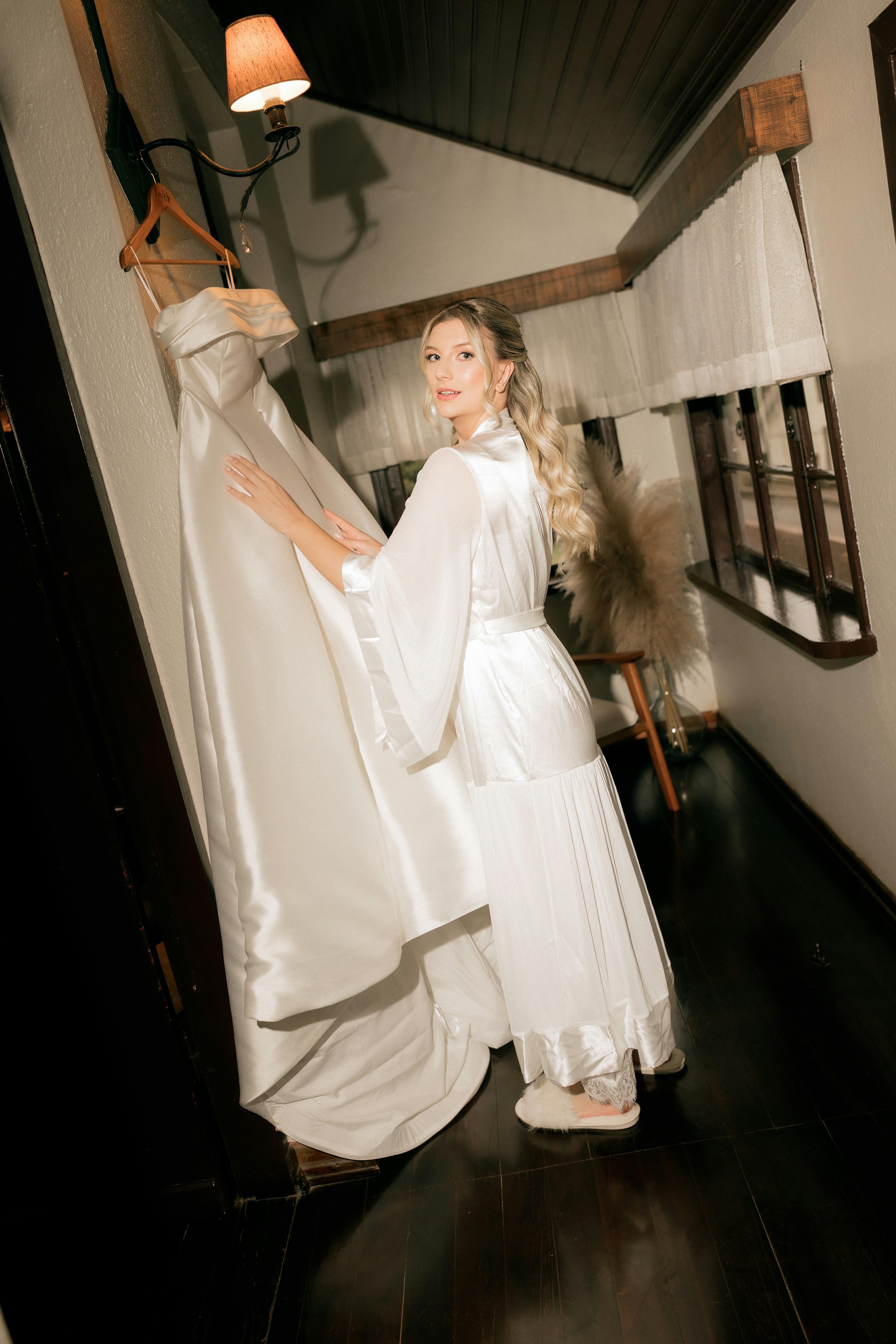 Bride-to-be in a satin gown gazes over her shoulder in a vintage dressing hallway