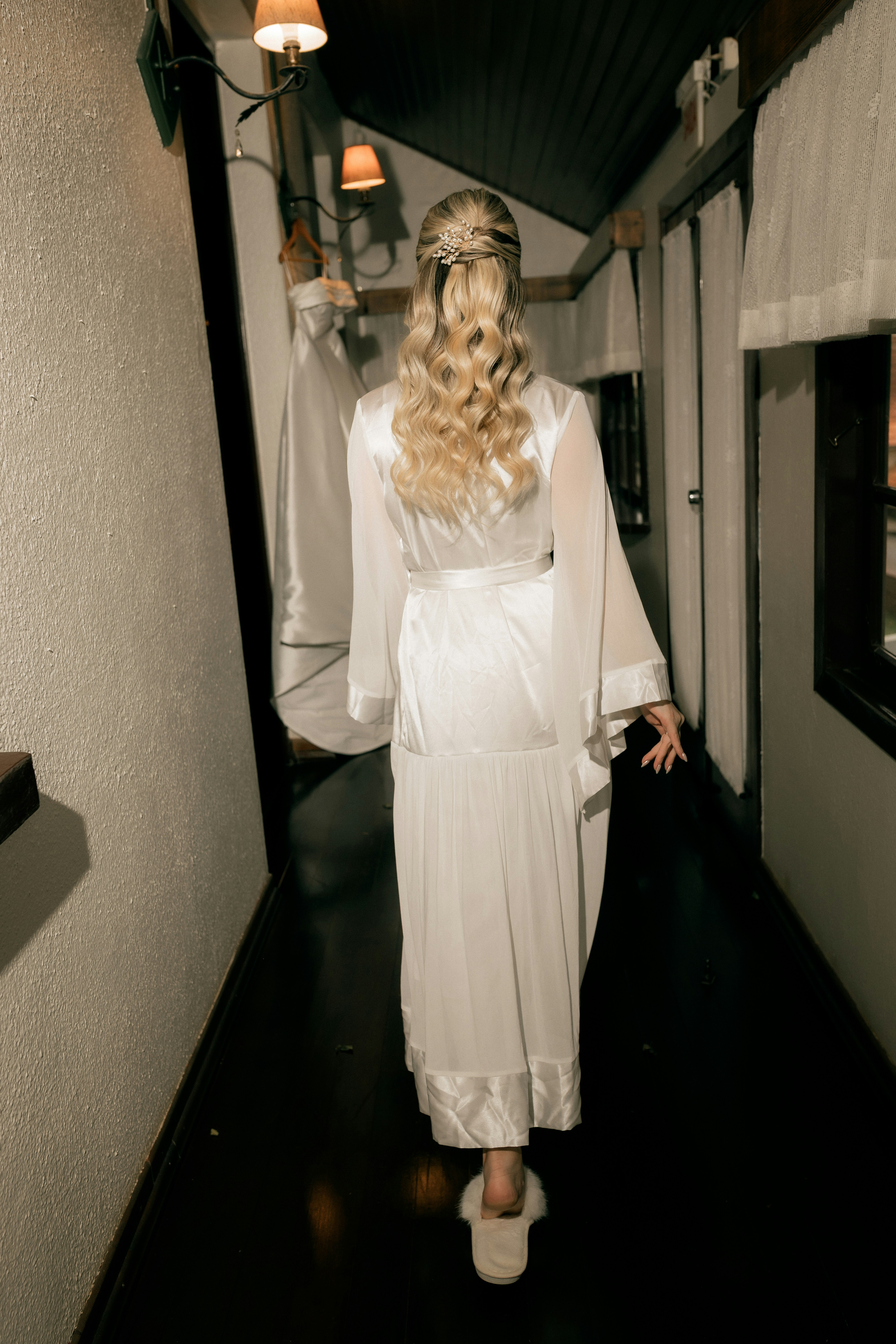 Backlit Bride in a White Robe Walking Down a Narrow Corridor