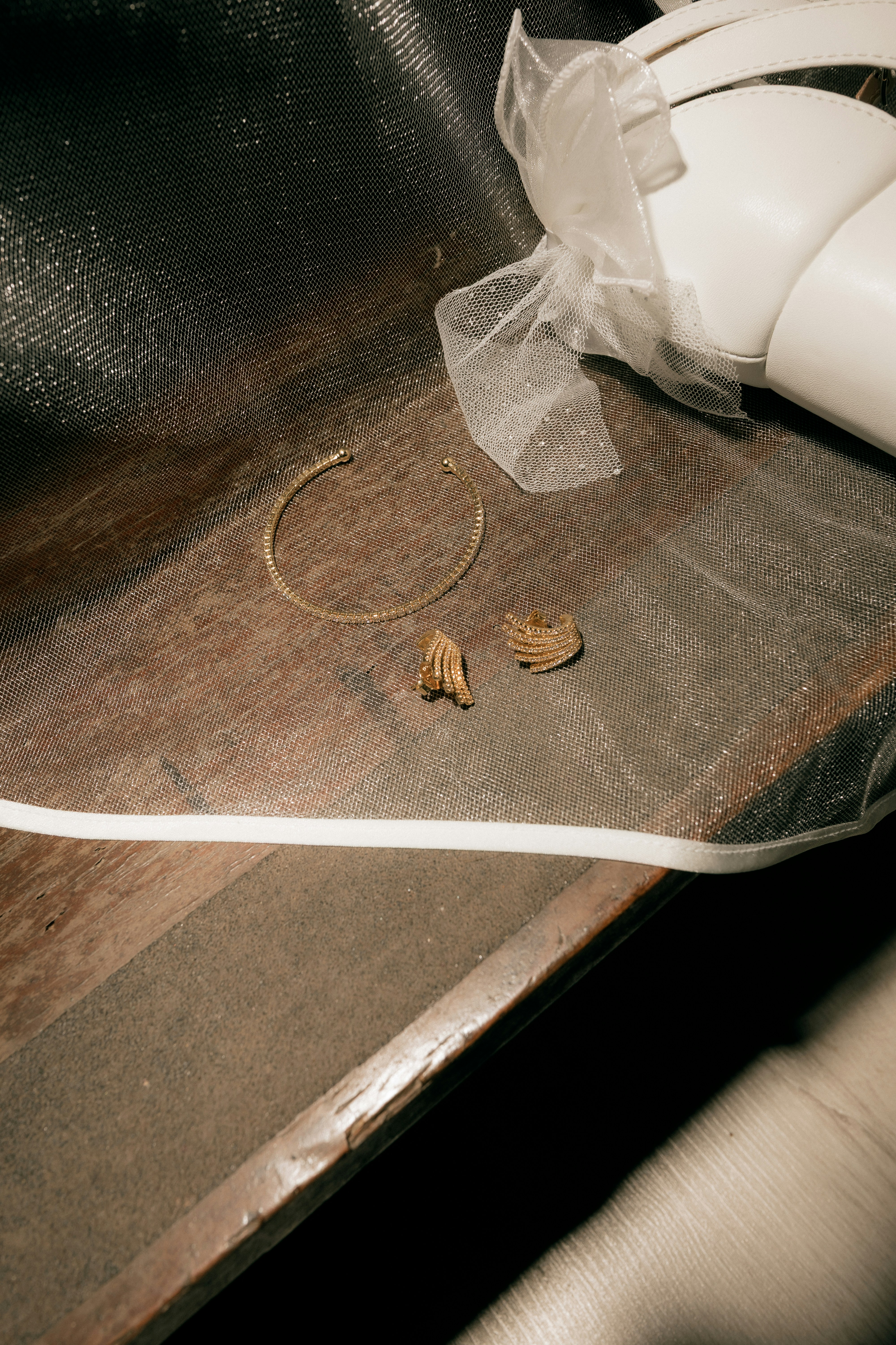 Remnants on a Weathered Surface: Jewelry Fragments Amid Tulle and Cord