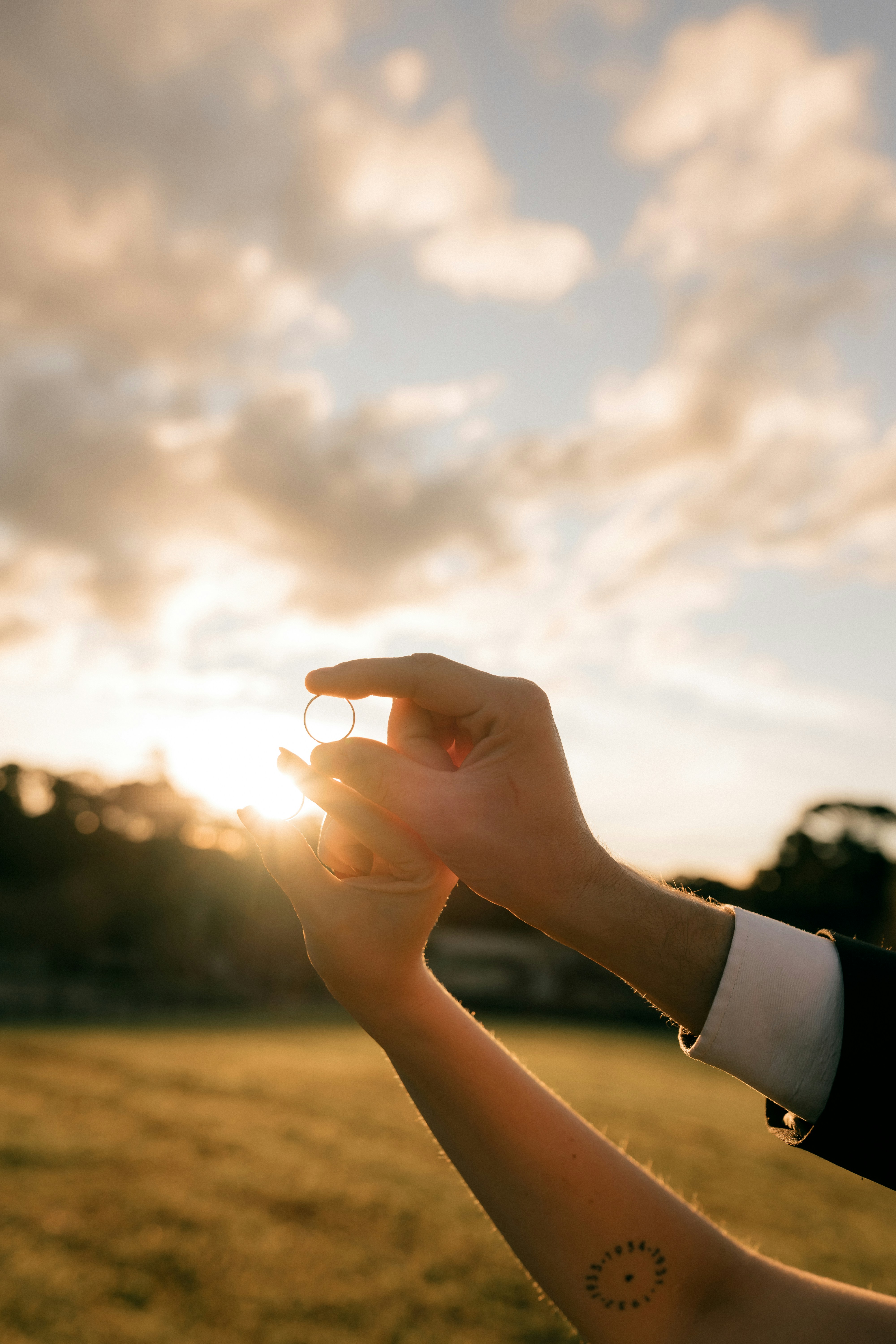 Sunset Ring: A Couple Holds a Delicate Moment Against the Golden Sky