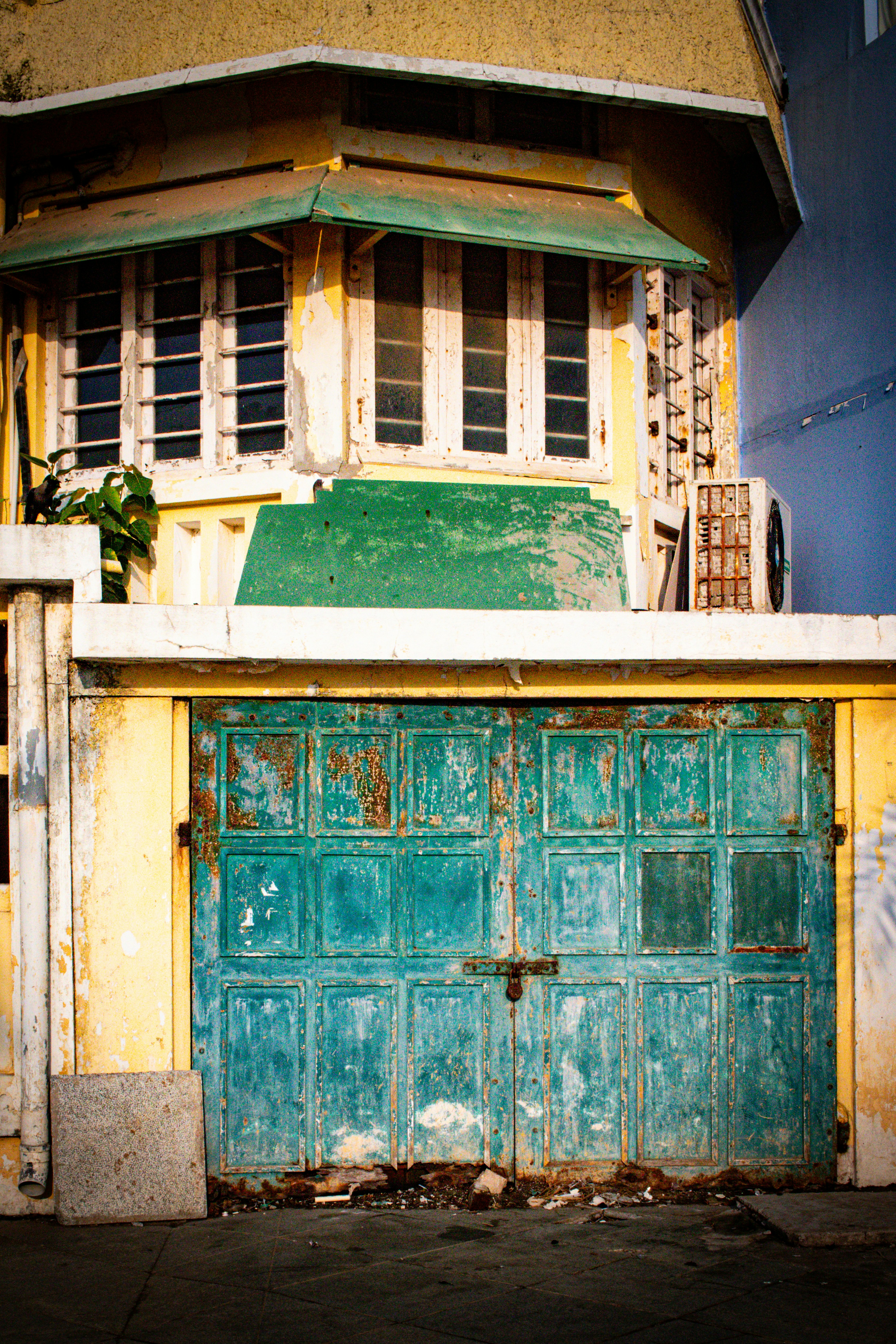 Weathered Green Garage Doors Beneath a Yellow-Washed Studio Window