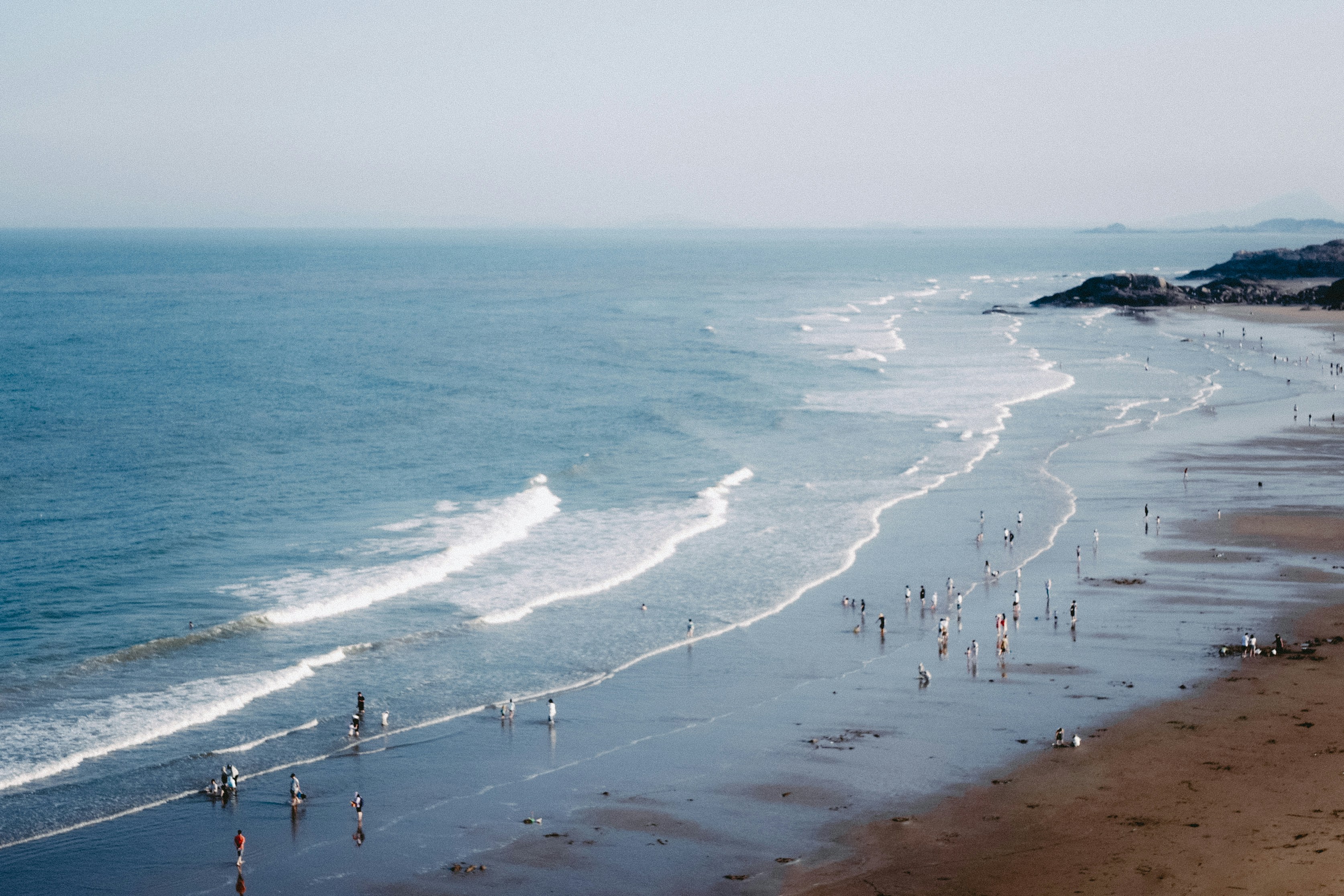 Coastal Cadence: People Dancing with the Tide along a Broad Shore