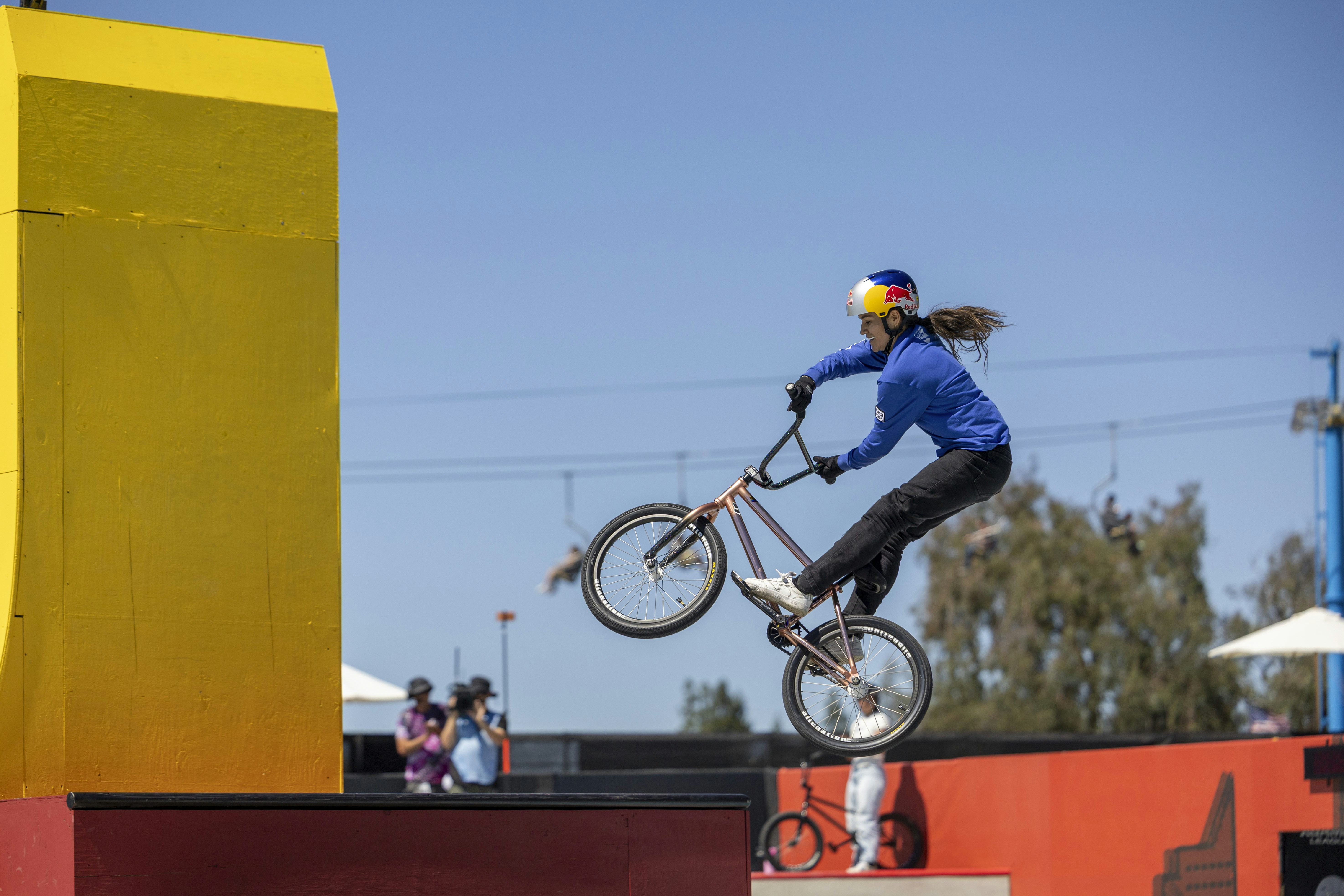 High-flying rider over a red obstacle under clear blue sky