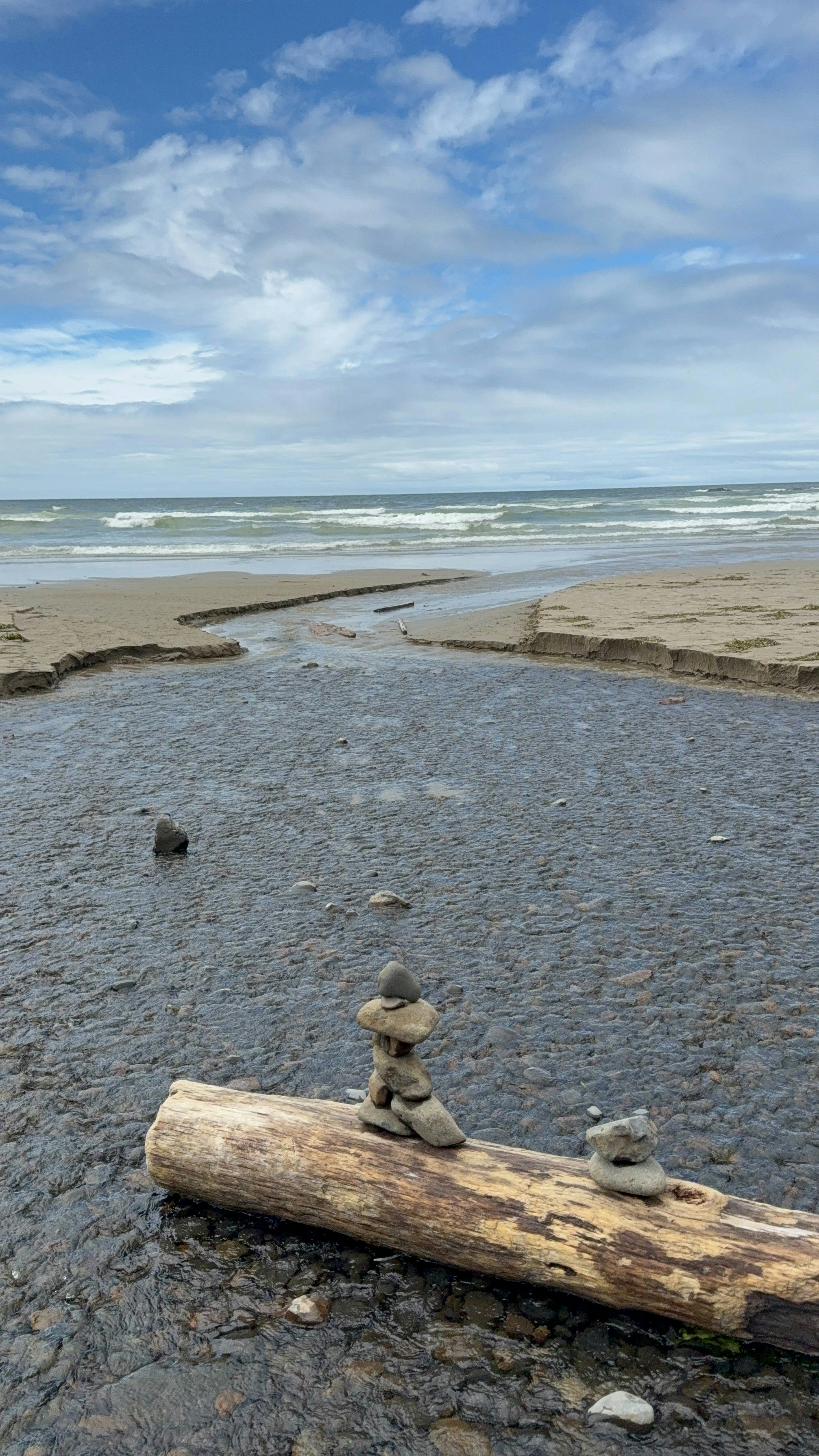 Balanced Tides: Pebble Stack on Drifted Log at Shoreline