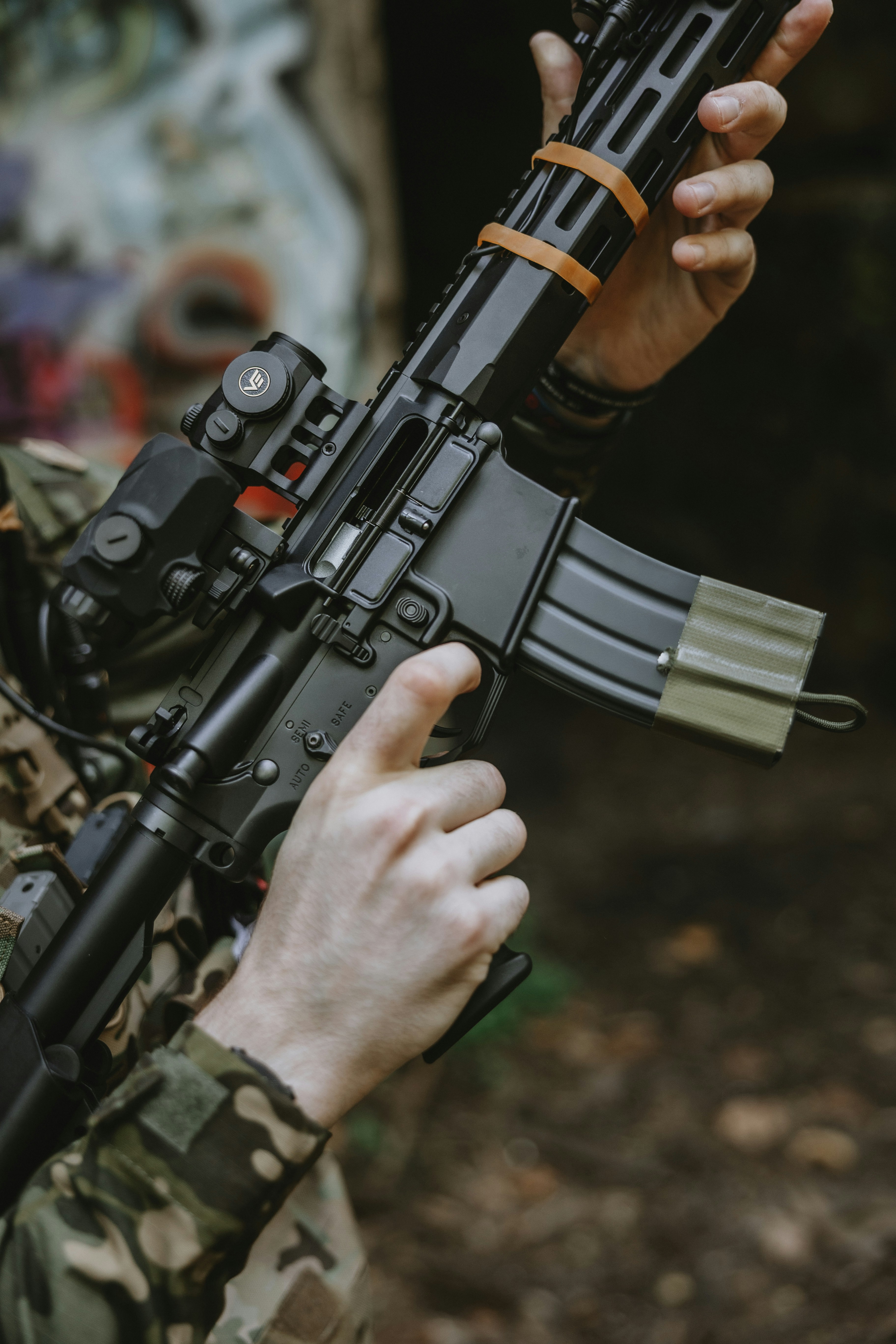 Close-up of a shooter gripping an AR-style rifle with a mounted optic; the image emphasizes the hand placement and control around the receiver and rail system. Photograph type: photograph of a firearm.