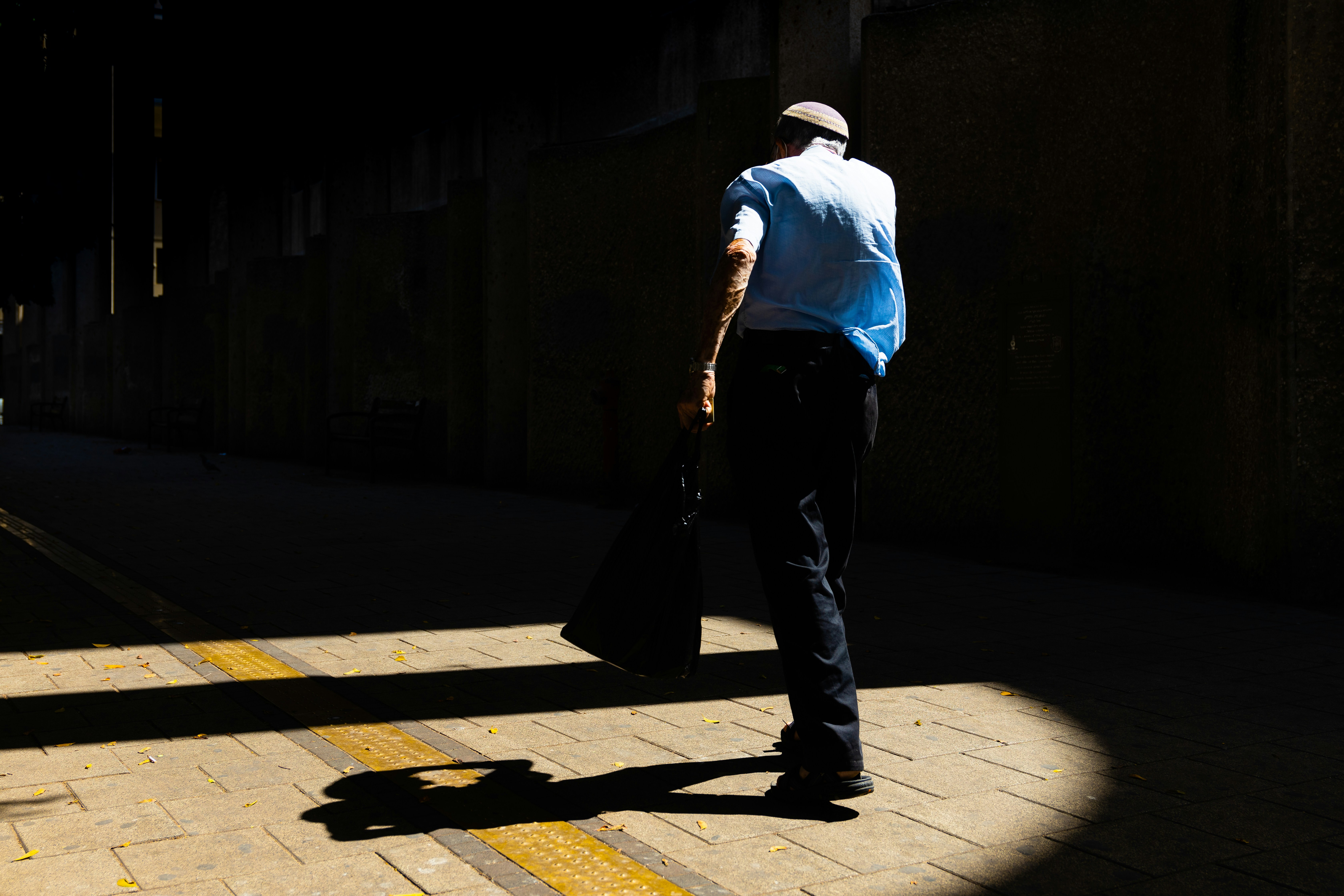 Shadowed Pedestrian with Bright Path: A Single Figure in a Sunlit Tile Corridor