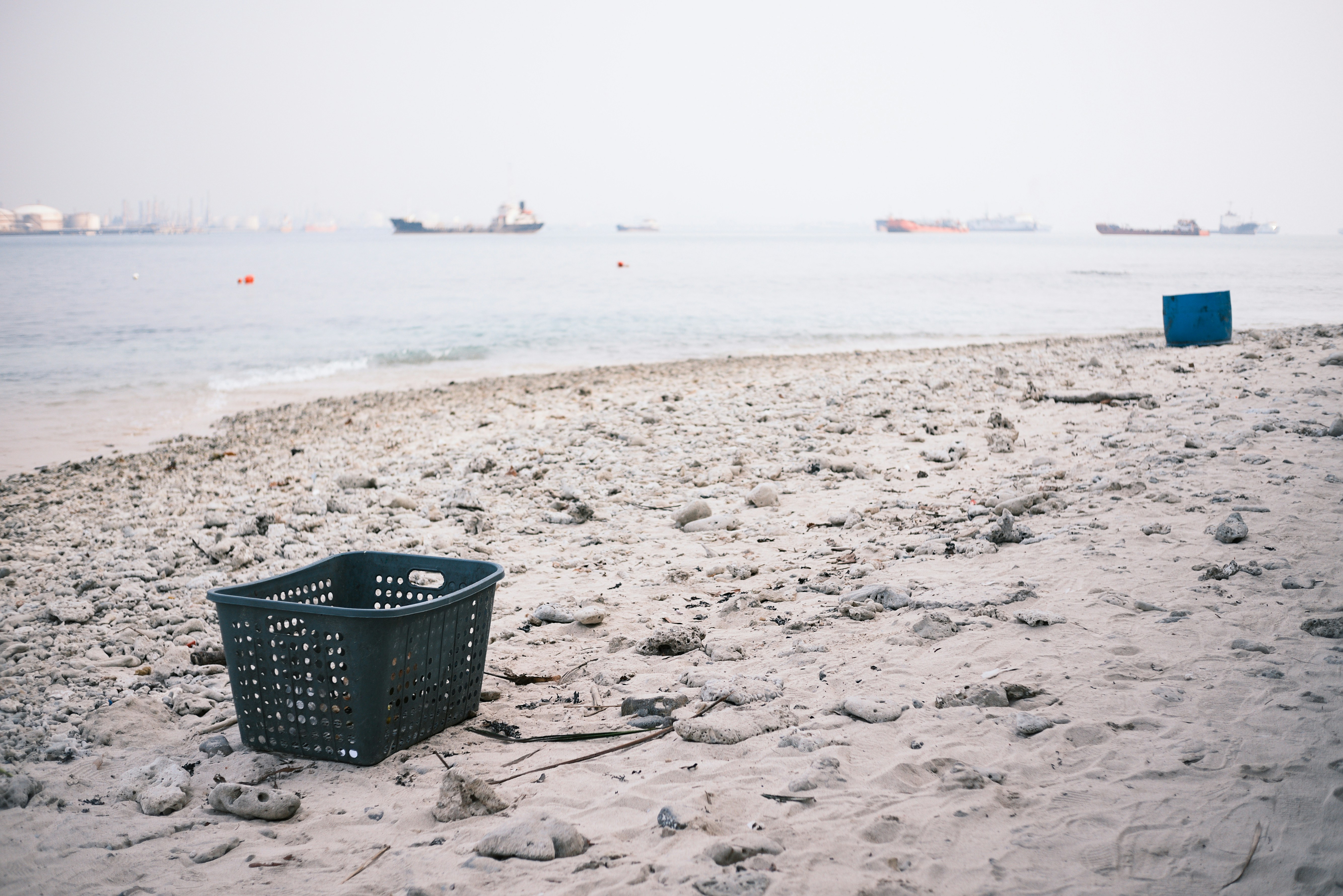 Basket on the Shore: A Quiet Strand with Distant Boats