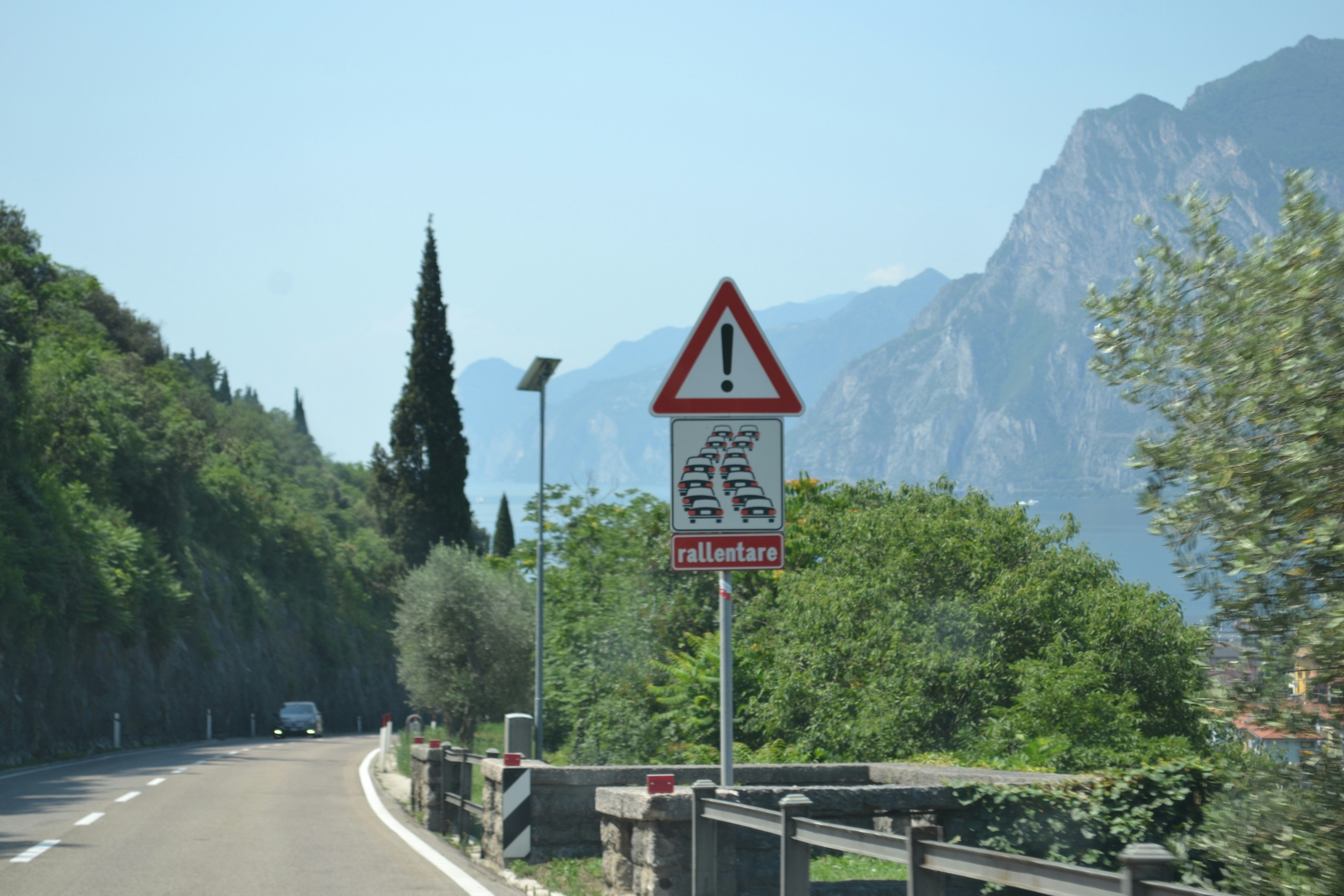 Twisting Road Beneath a Warning Sign Under Alpine Skies