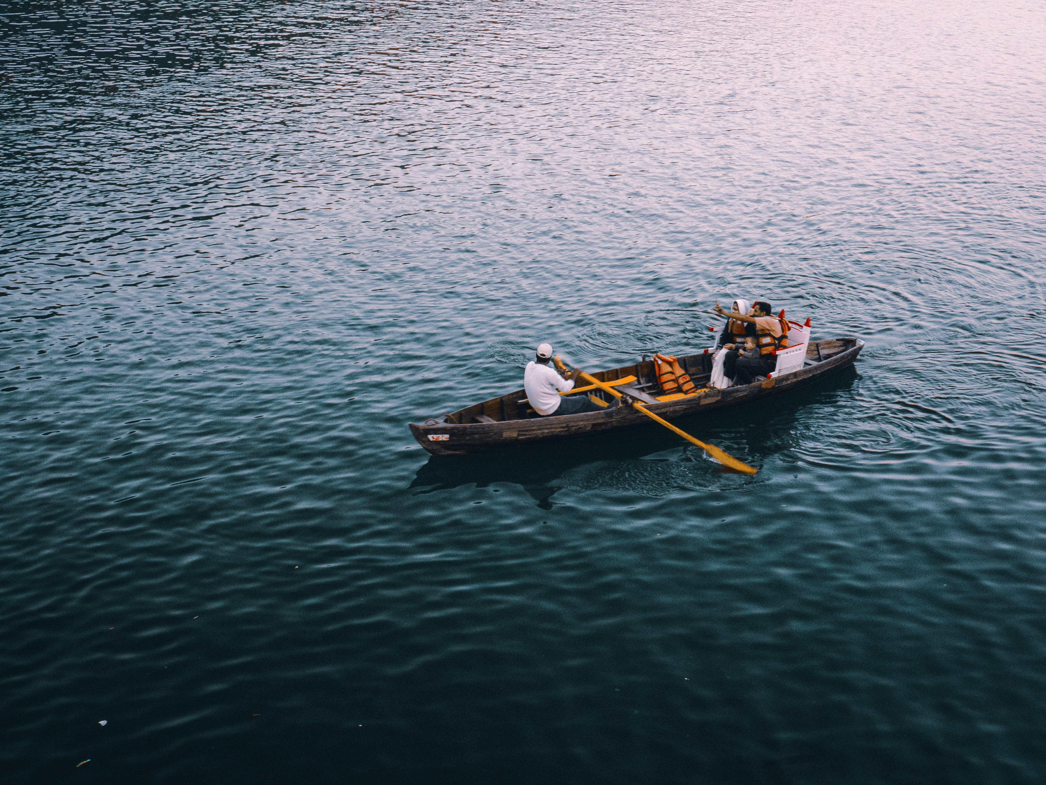 Rowers in a Quiet Sea: A Lone Boat Carves Across Blue-Turquoise Water