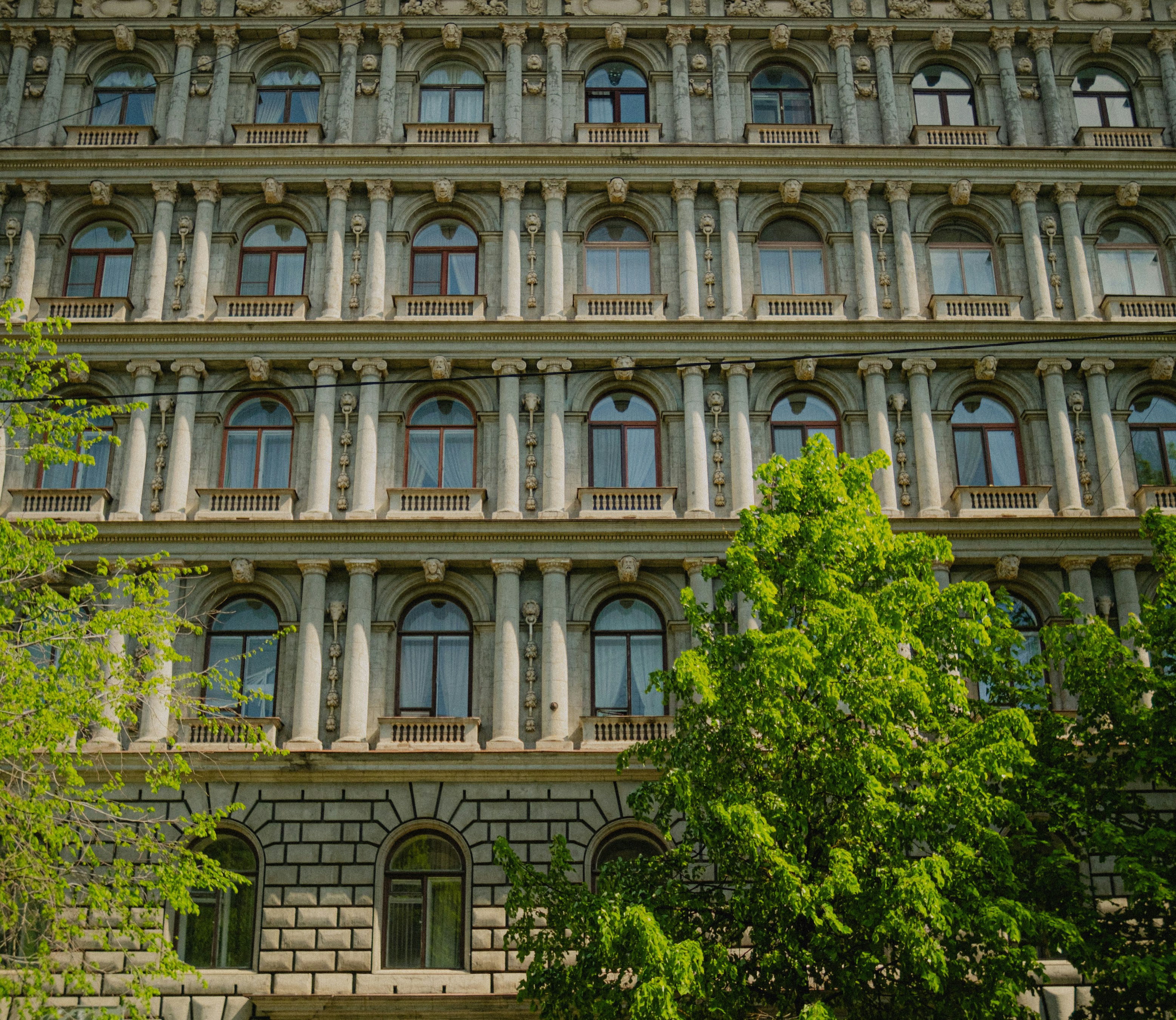 Urban Facade in Bloom: A Historic Building Framed by Fresh summer Foliage