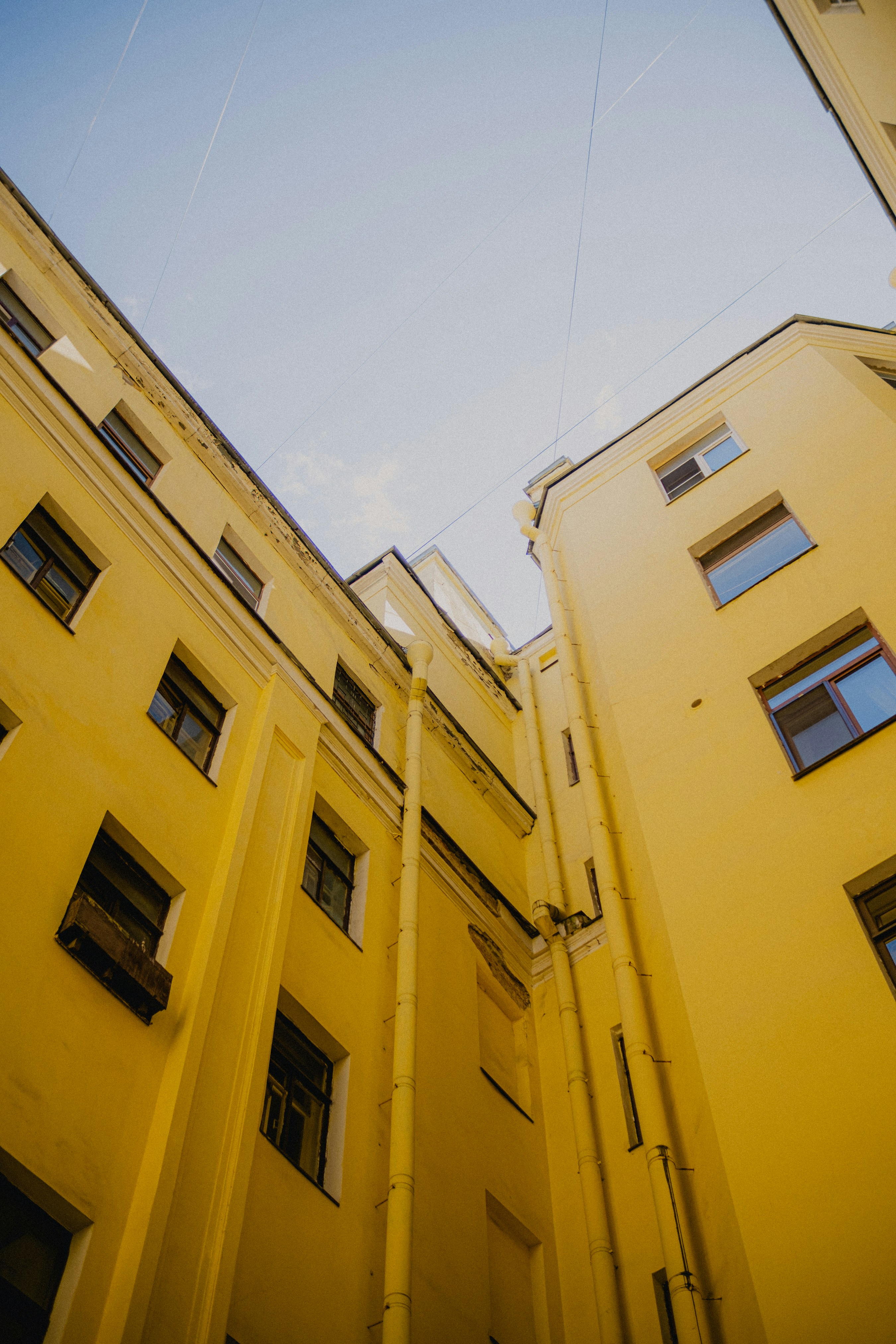 Canted Skyward Canyon: Yellow Facades Converging Under Open Blue