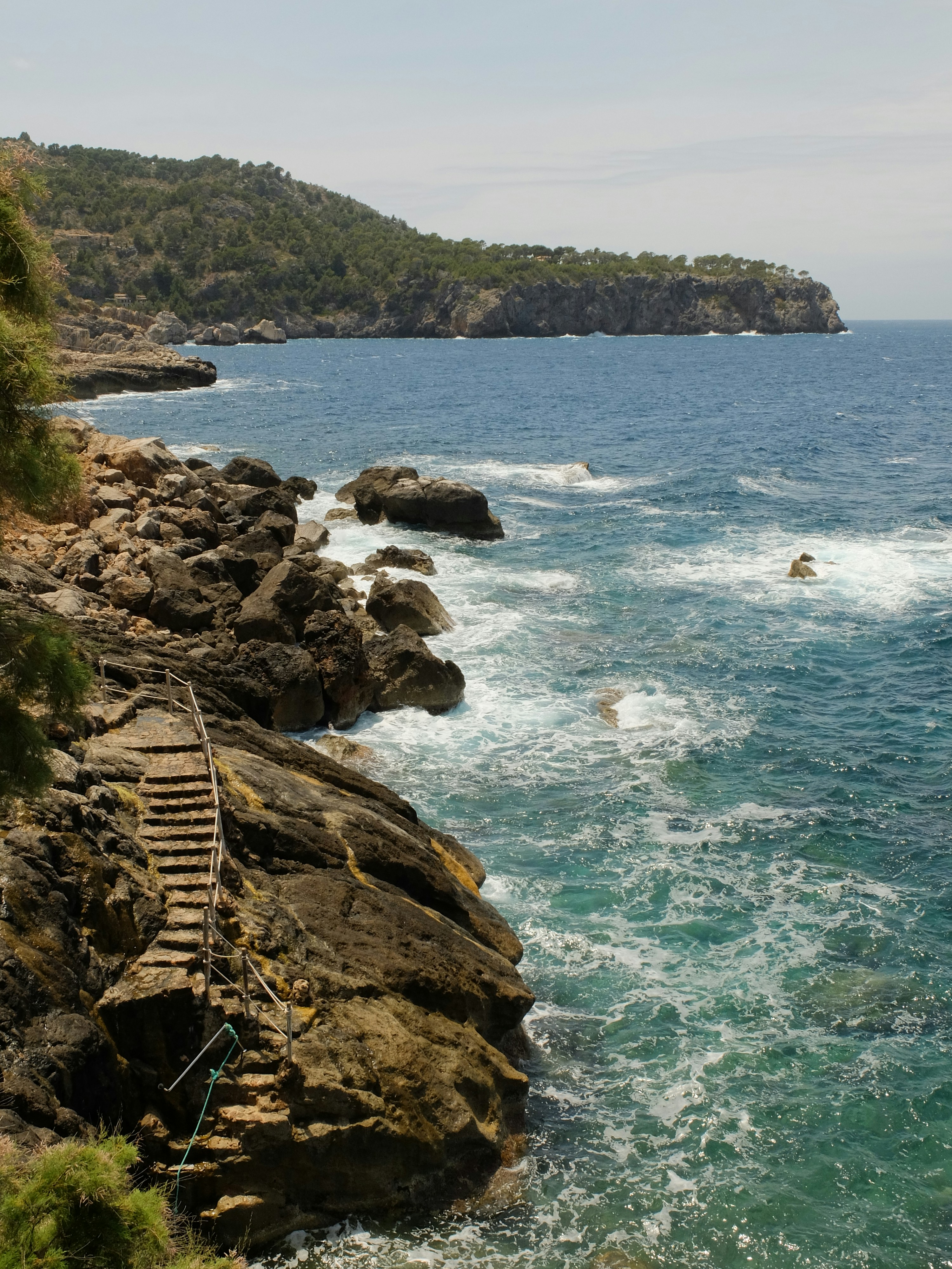 Sunlit Cliffs and Turquoise Surge along a Rocky Cove