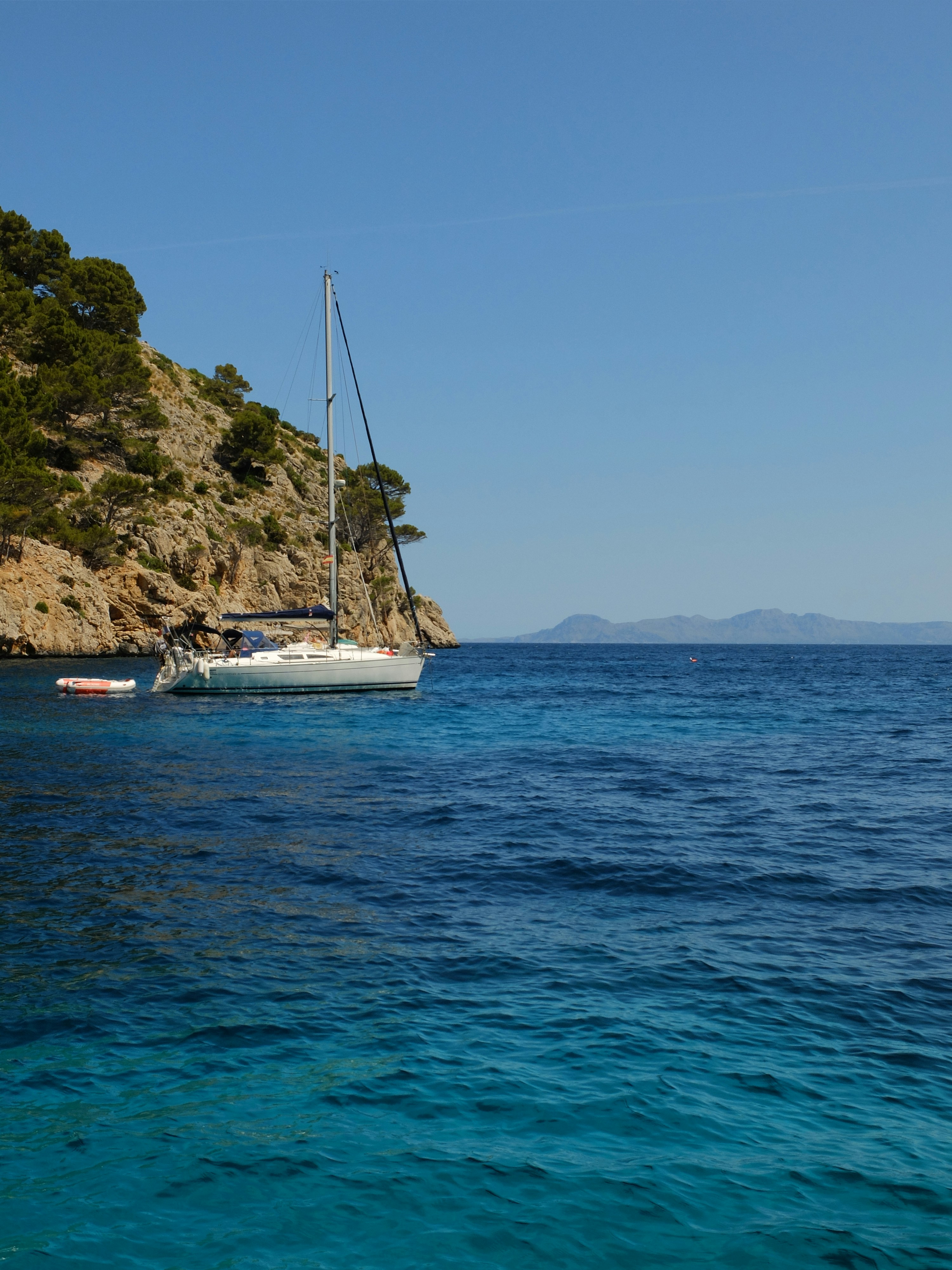 Sailboat at the Ledge: Quiet Blue Waters by a Cliff