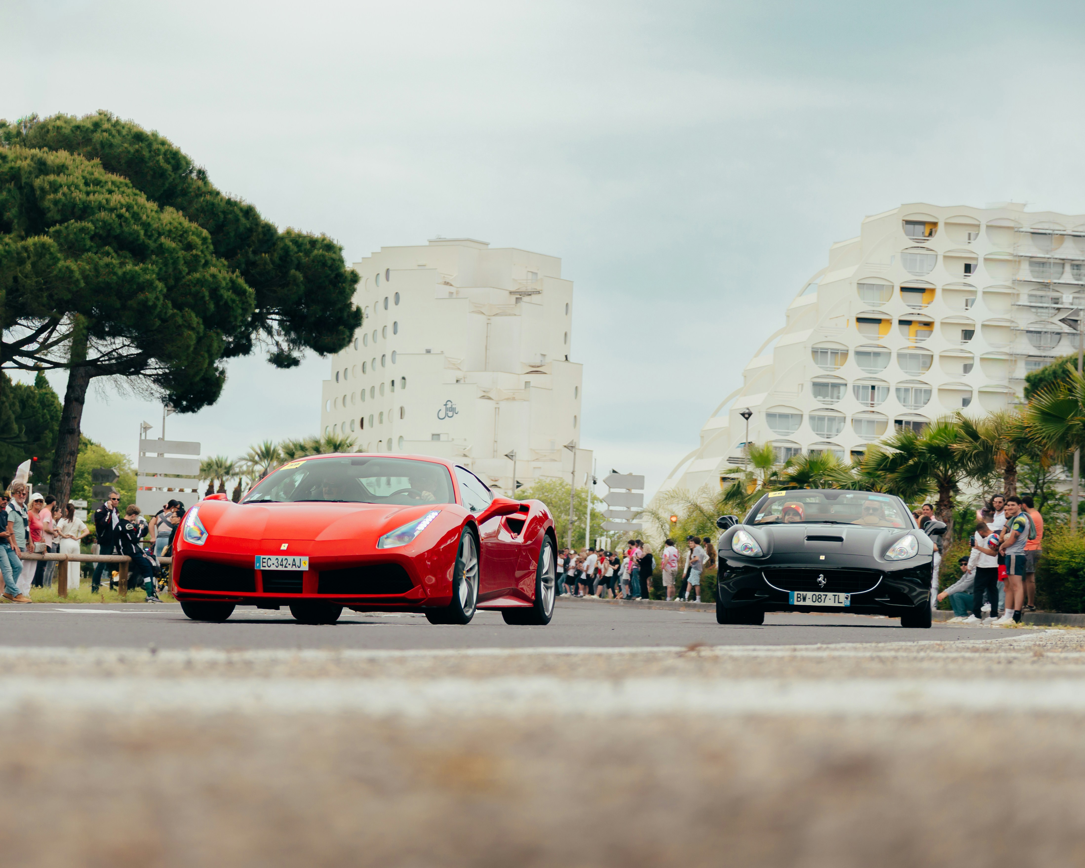 Two Exotic Sports Cars Roar Past a Modern Coastal Boulevard